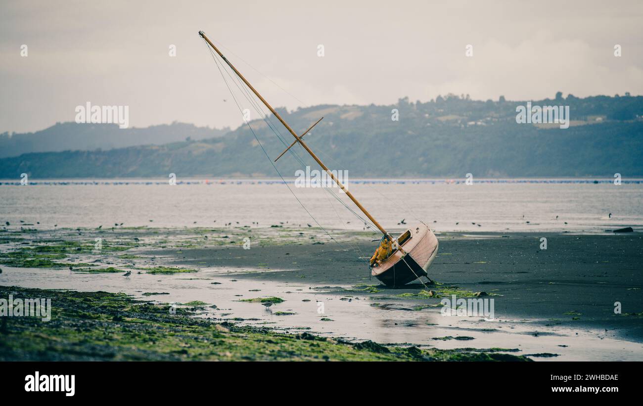 A sailing boat lies dry on land on Chiloe during low tide Stock Photo ...
