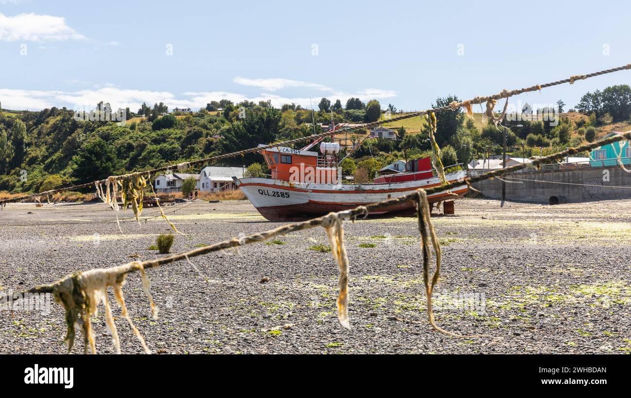 A fishing boat stranded ashore on a sandbank on Chiloe during low tide ...