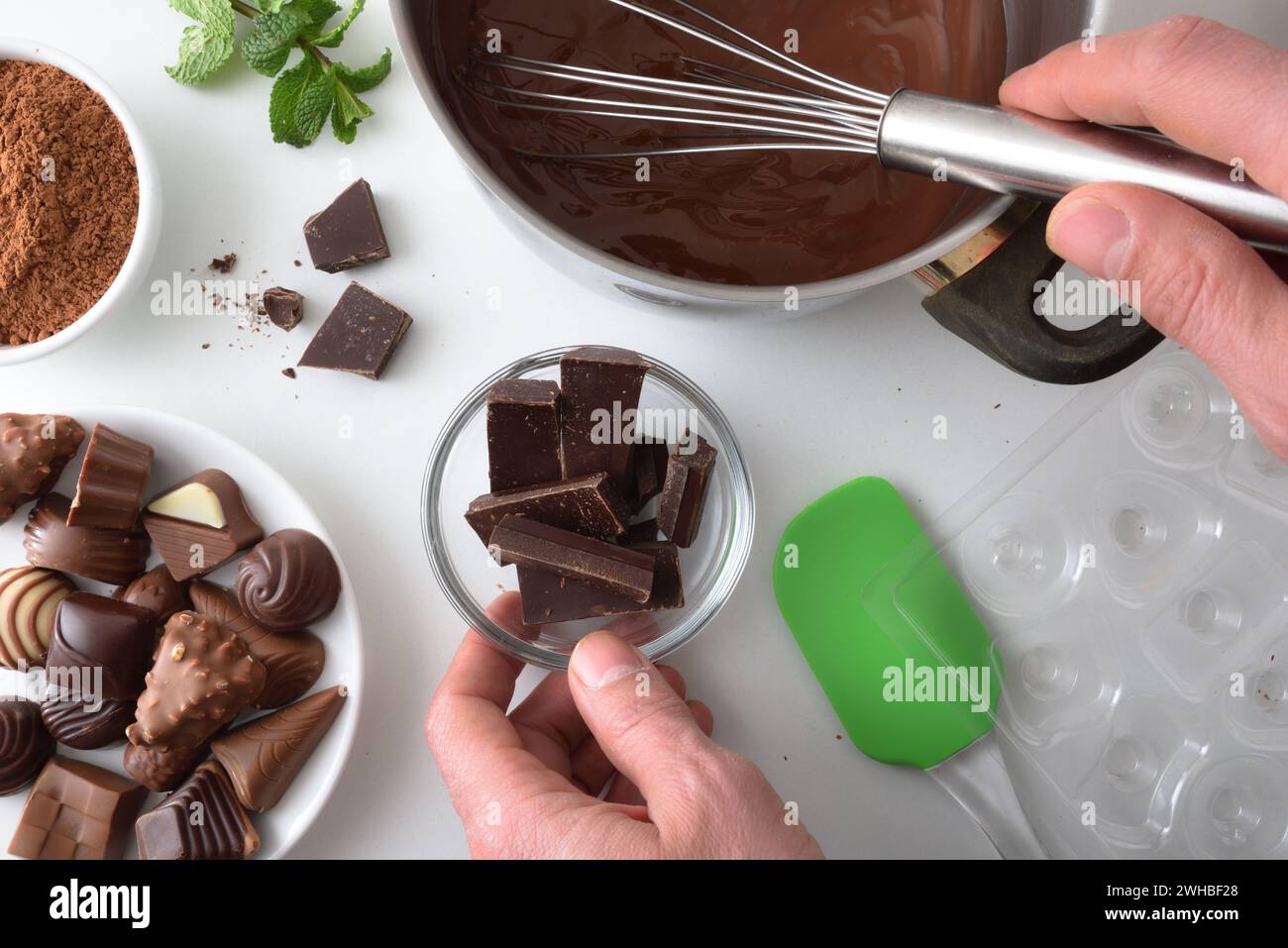 Person making homemade chocolate bonbons on white kitchen bench at home ...
