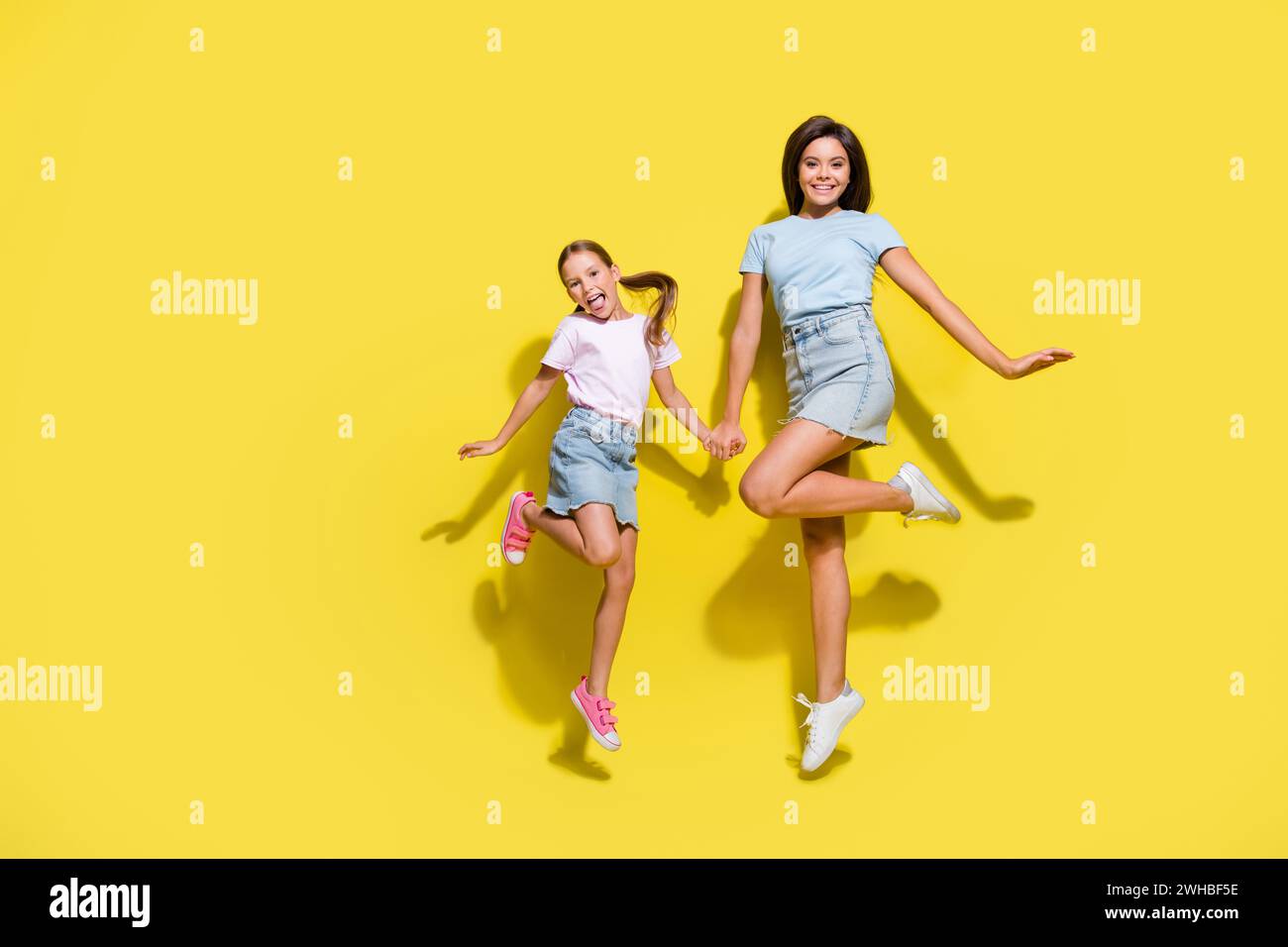 Photo of two positive cheerful girls enjoy together on summer walk jump ...