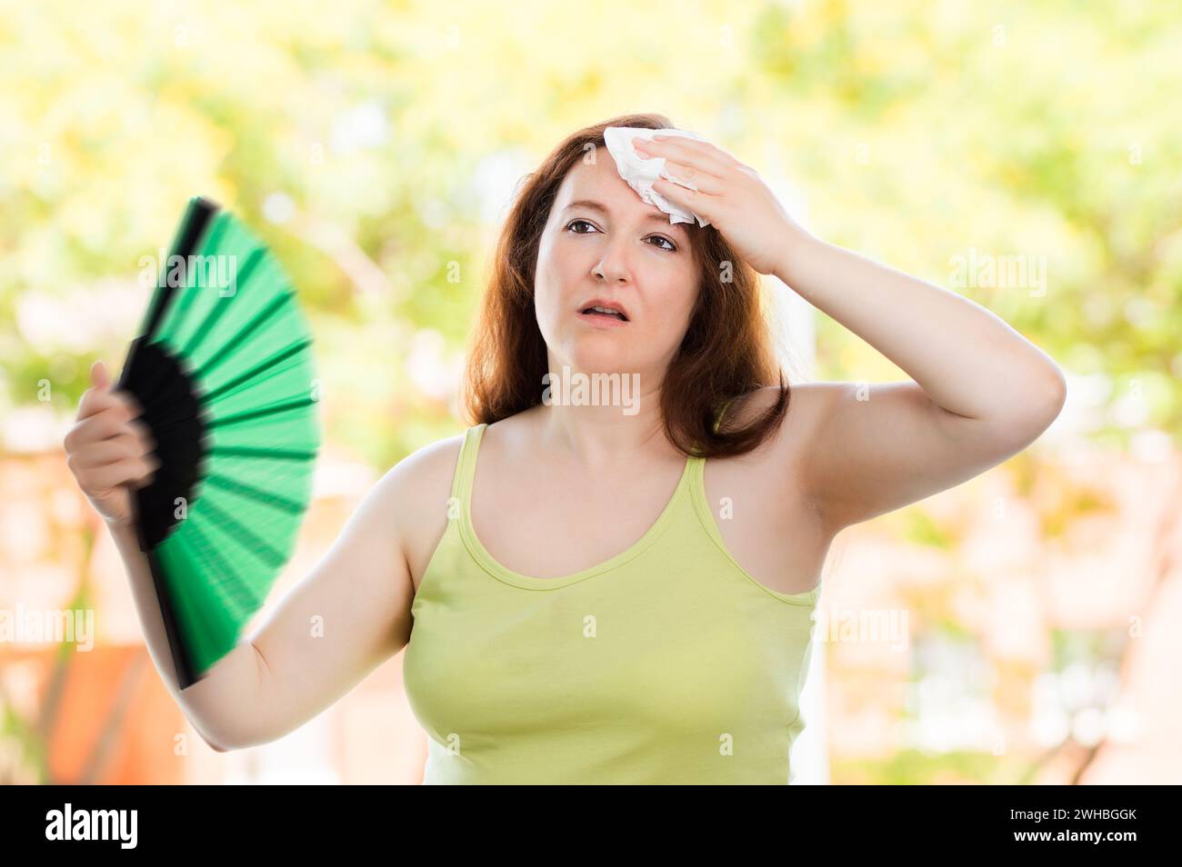 Shot of a sad woman fanning and sweating suffering a heat stroke at ...