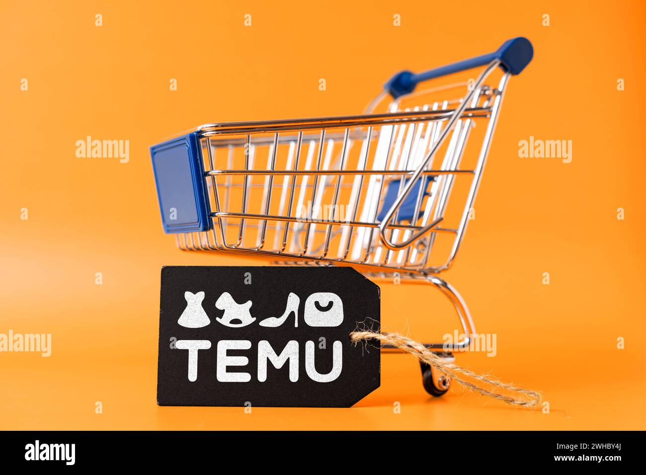 9 February 2024: Shopping cart against an orange background with a sign ...