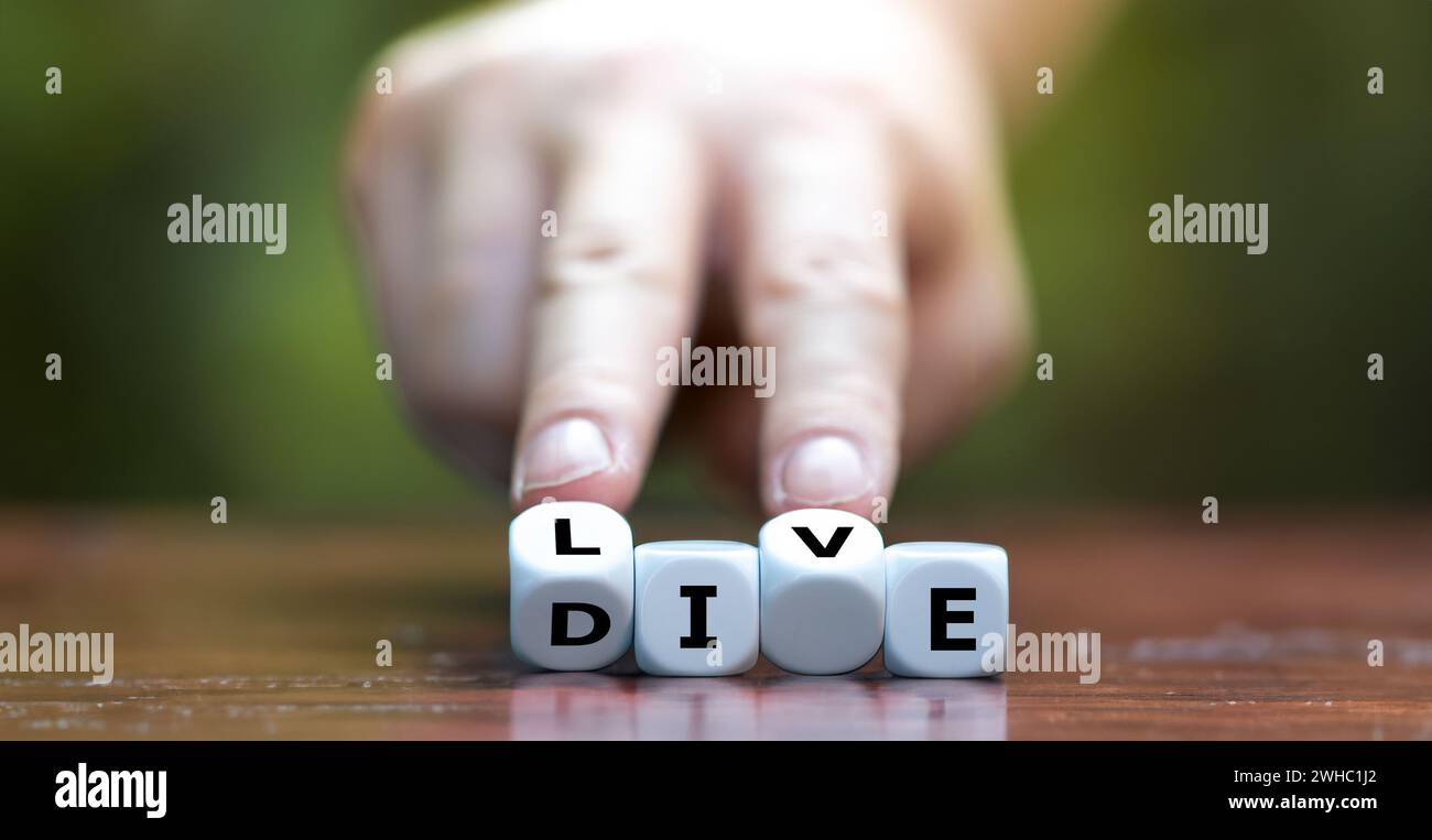 Hand turns dice and changes the word die to live Stock Photo - Alamy