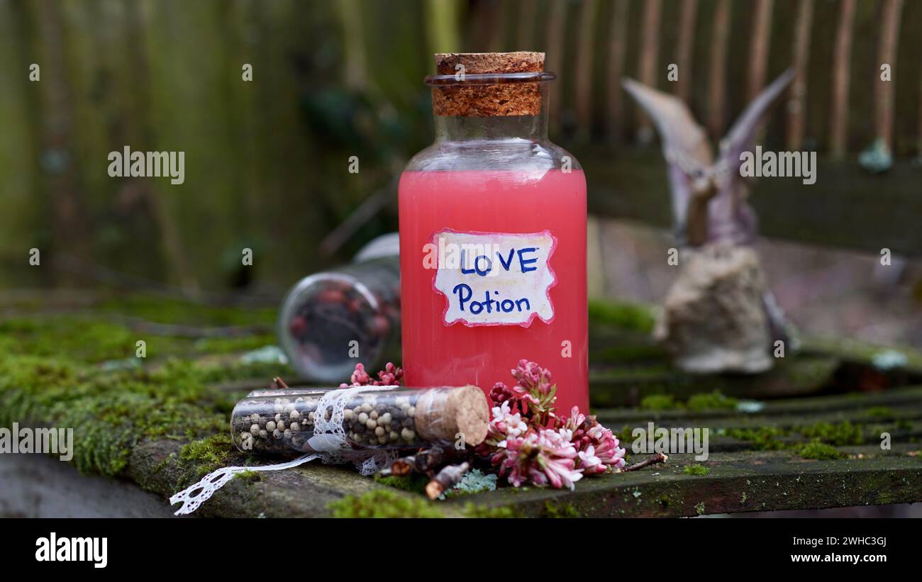 A glass bottle with love potion, blossoms, a small dragon, tubules with ...