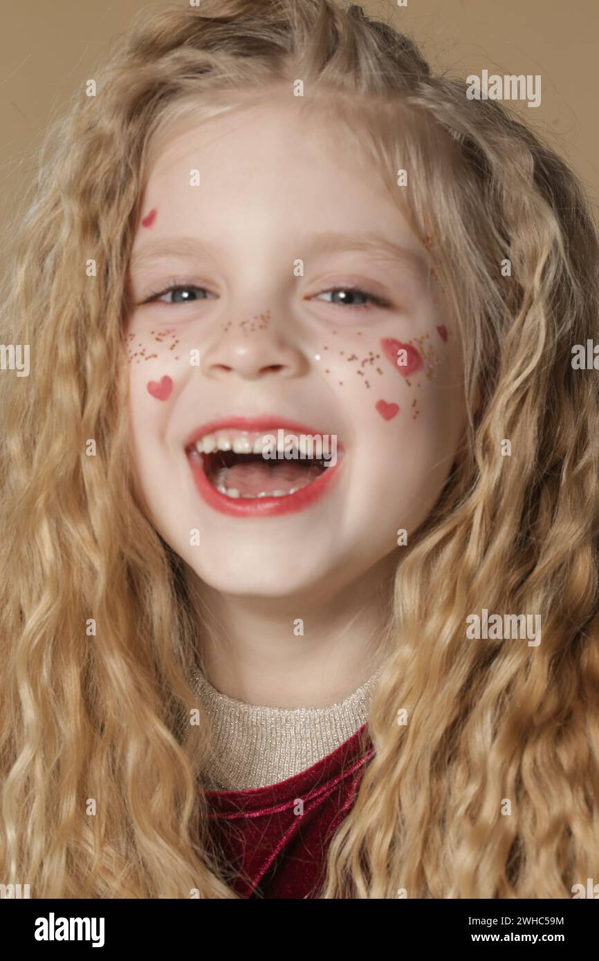 Portrait of cute little girl in red dress with long blonde hair and ...