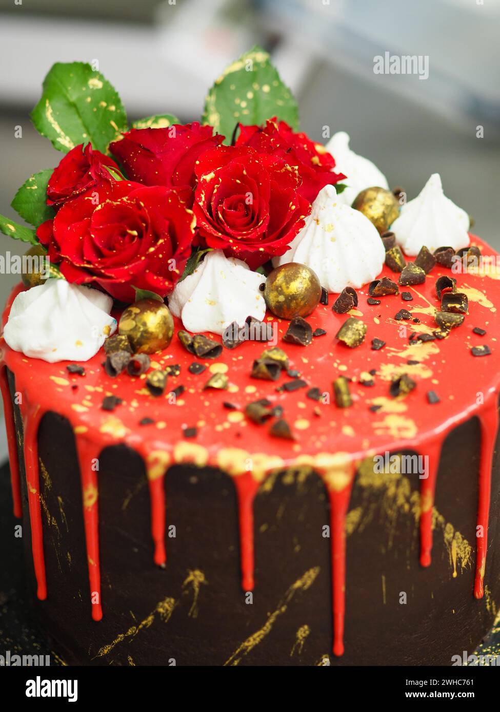 Luxurious cake with red dripping icing, roses, chocolates, and gold ...
