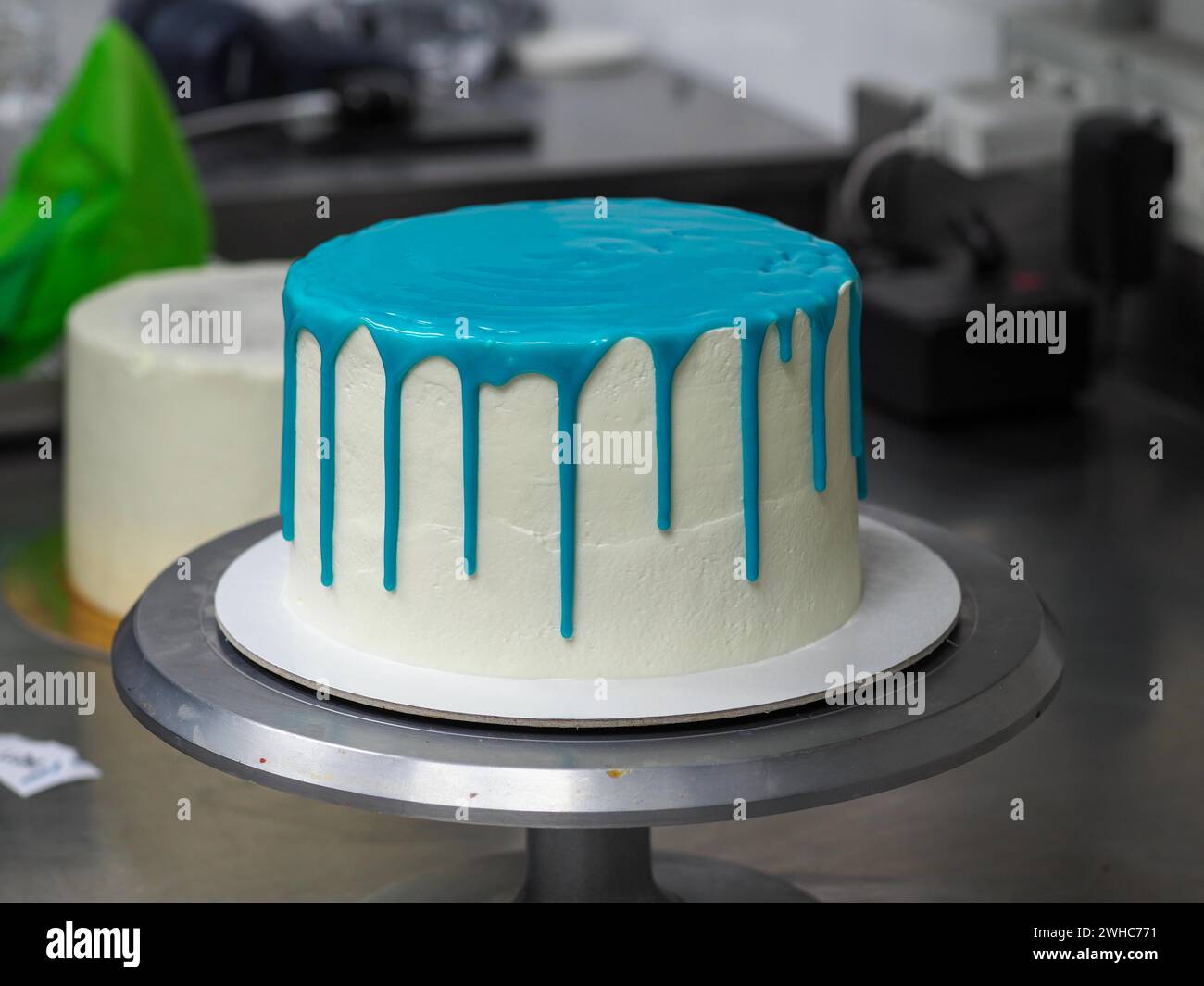 Fully iced white cake with blue drips on a rotating cake stand Stock ...