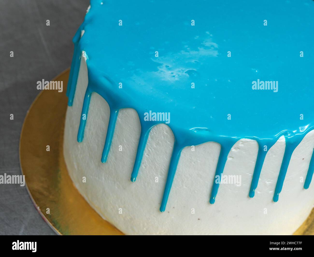 A white frosted cake with vibrant blue icing dripping down the sides on ...