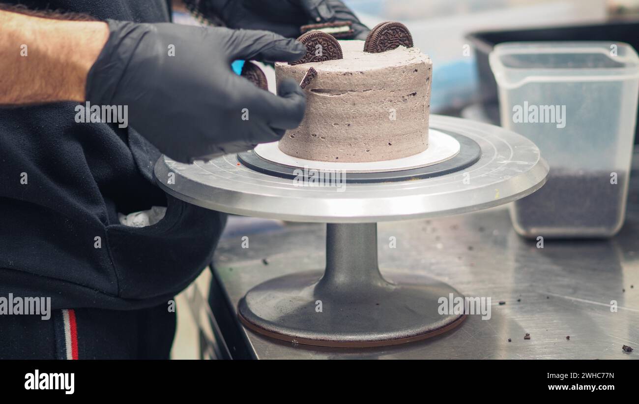 Hands of a chef adding dark chocolate cookies to top a creamy chocolate ...