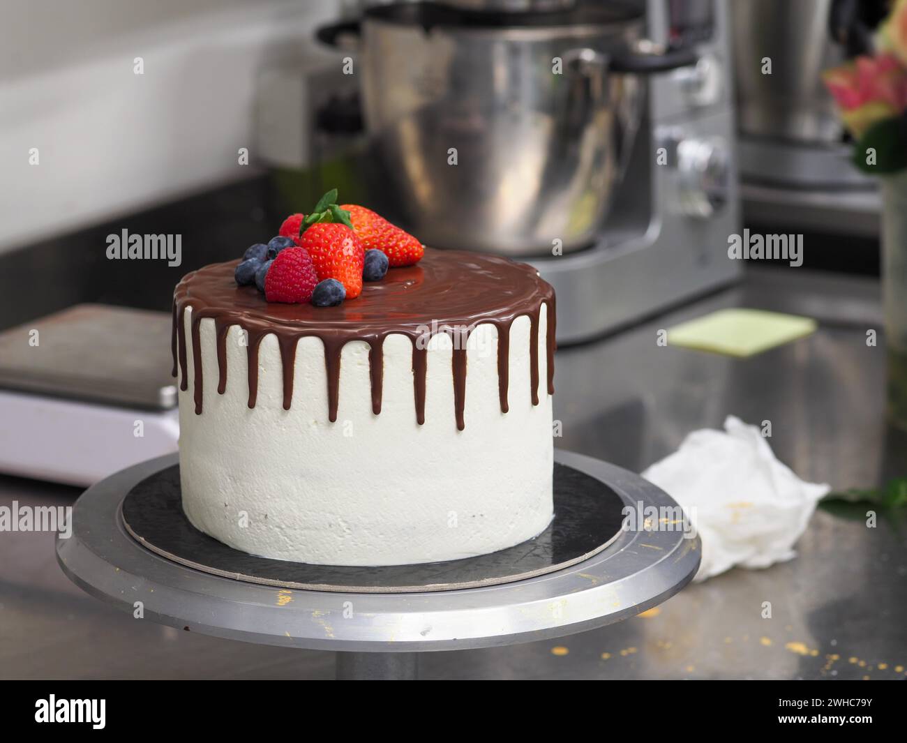 A finished chocolate drip cake topped with an assortment of fresh ...