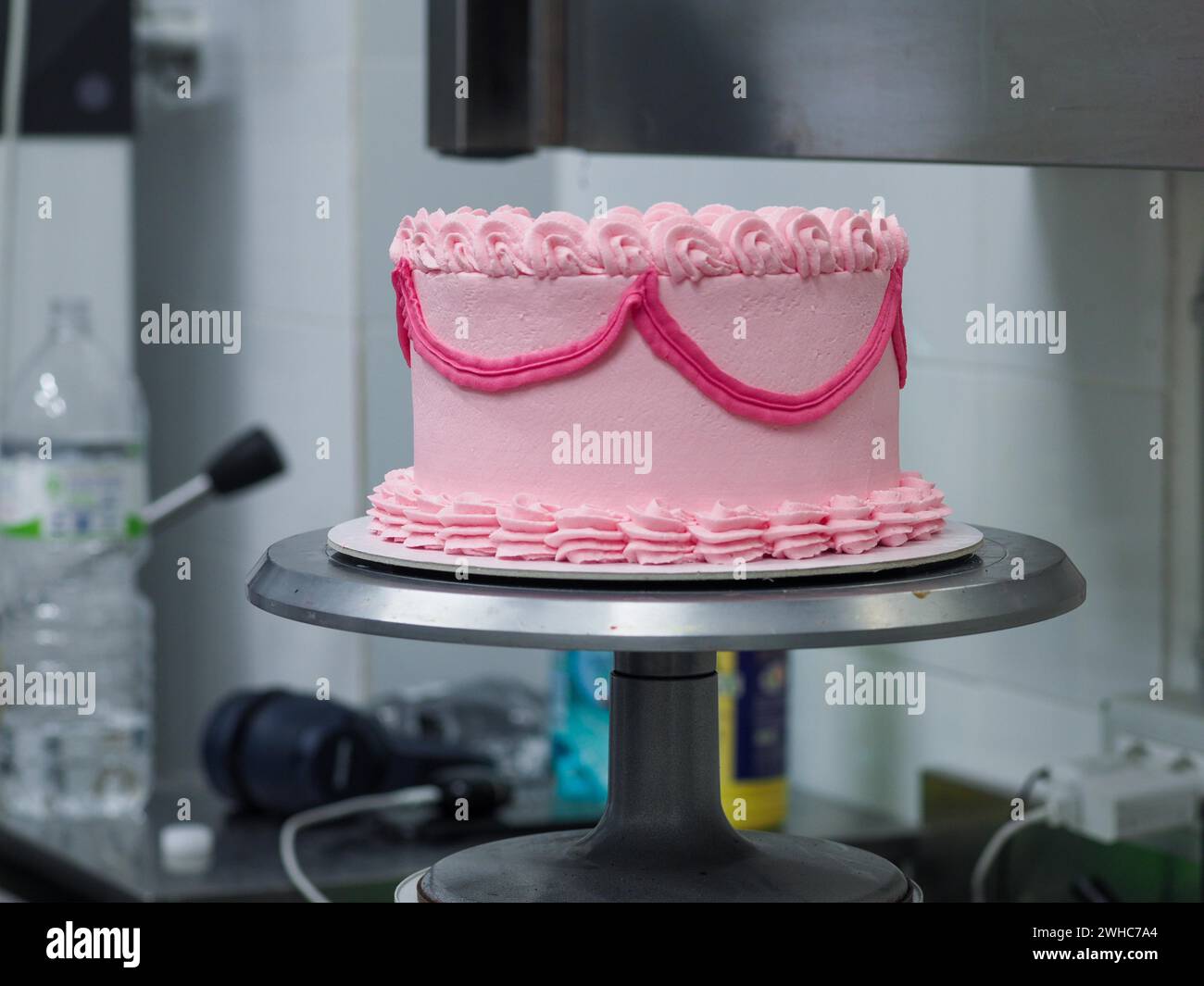 A pink ruffled cake displayed on a rotating stand in a professional ...