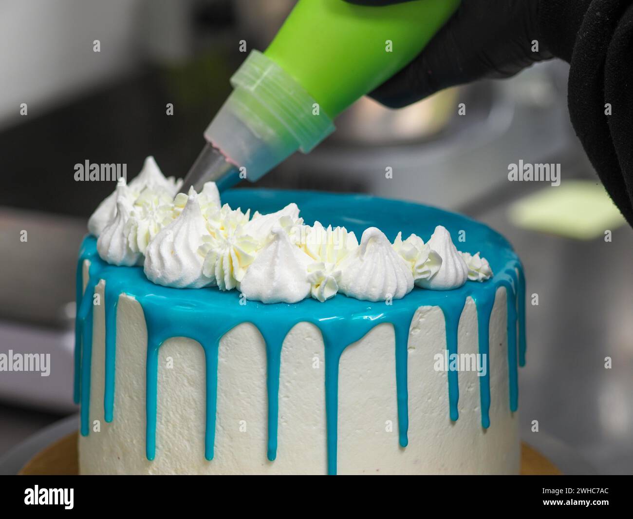 Decorating a cake with white icing using a pastry bag, with blue ...