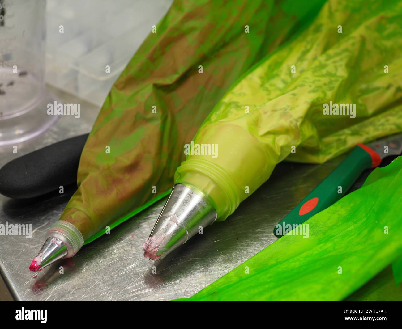 Close-up of a pastry bag with a metallic piping tip on a steel kitchen ...