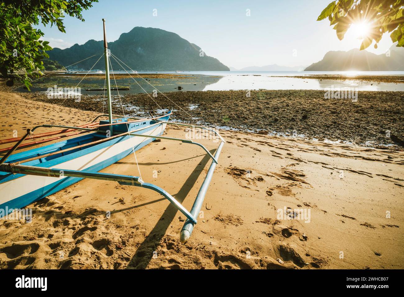 Bangka boat on sandy beach with golden sunset light over tropical ...