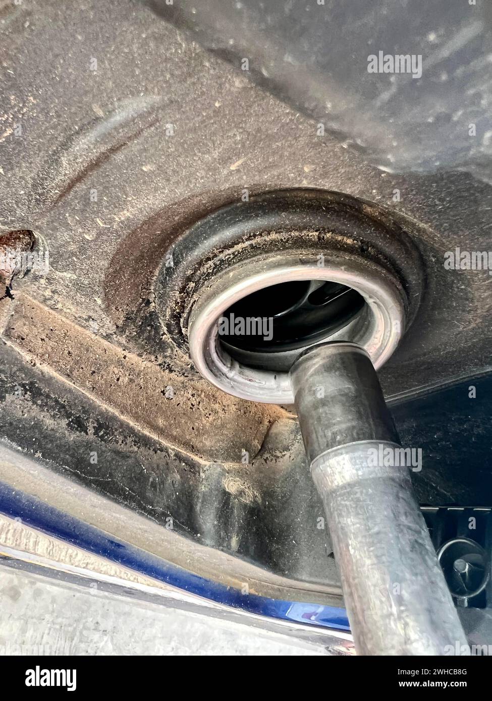 Detail of a person's hand pouring gas into a car at a gas station ...