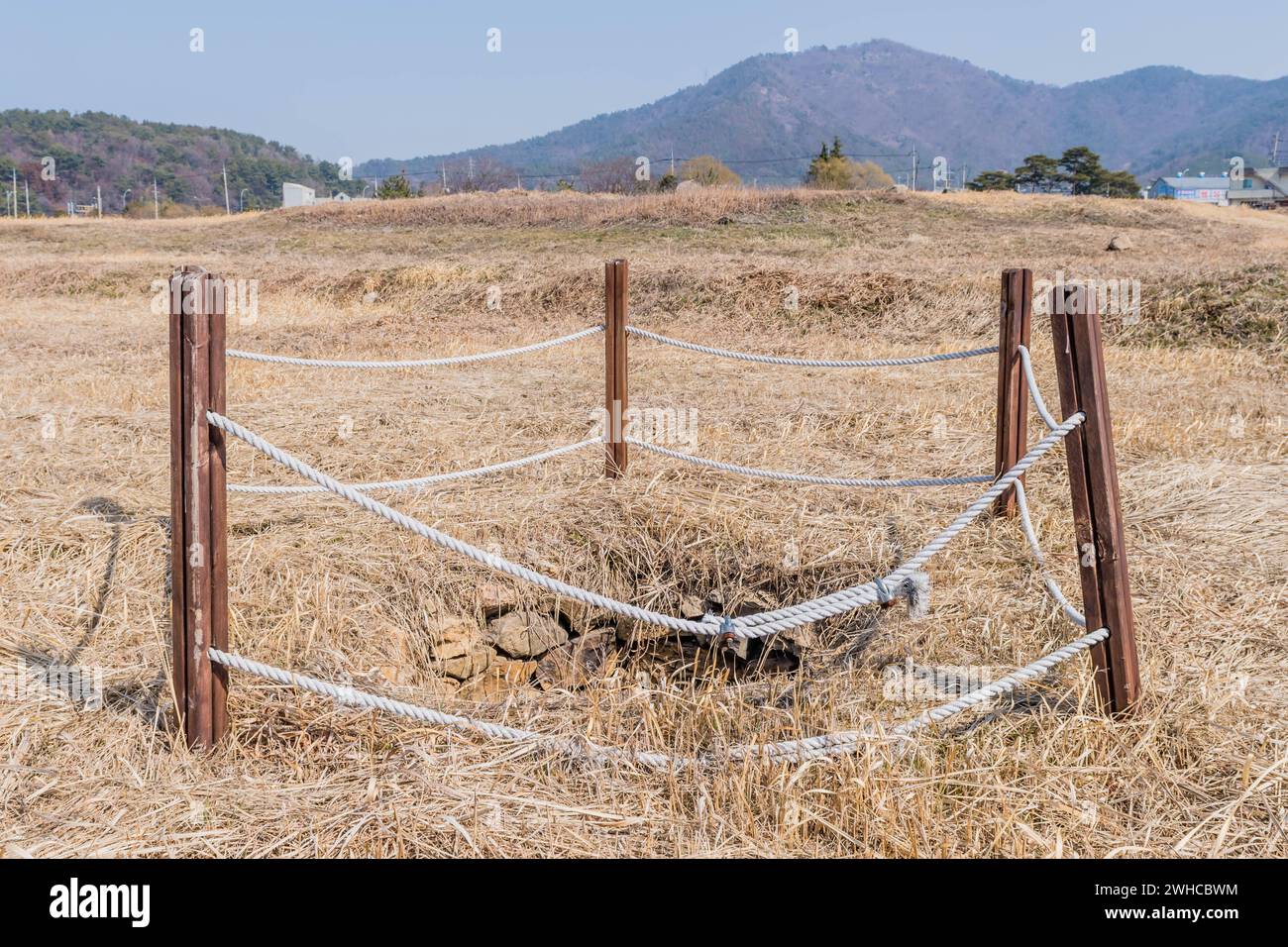 Water well cordoned off with wooden beams and rope at remains of stone ...