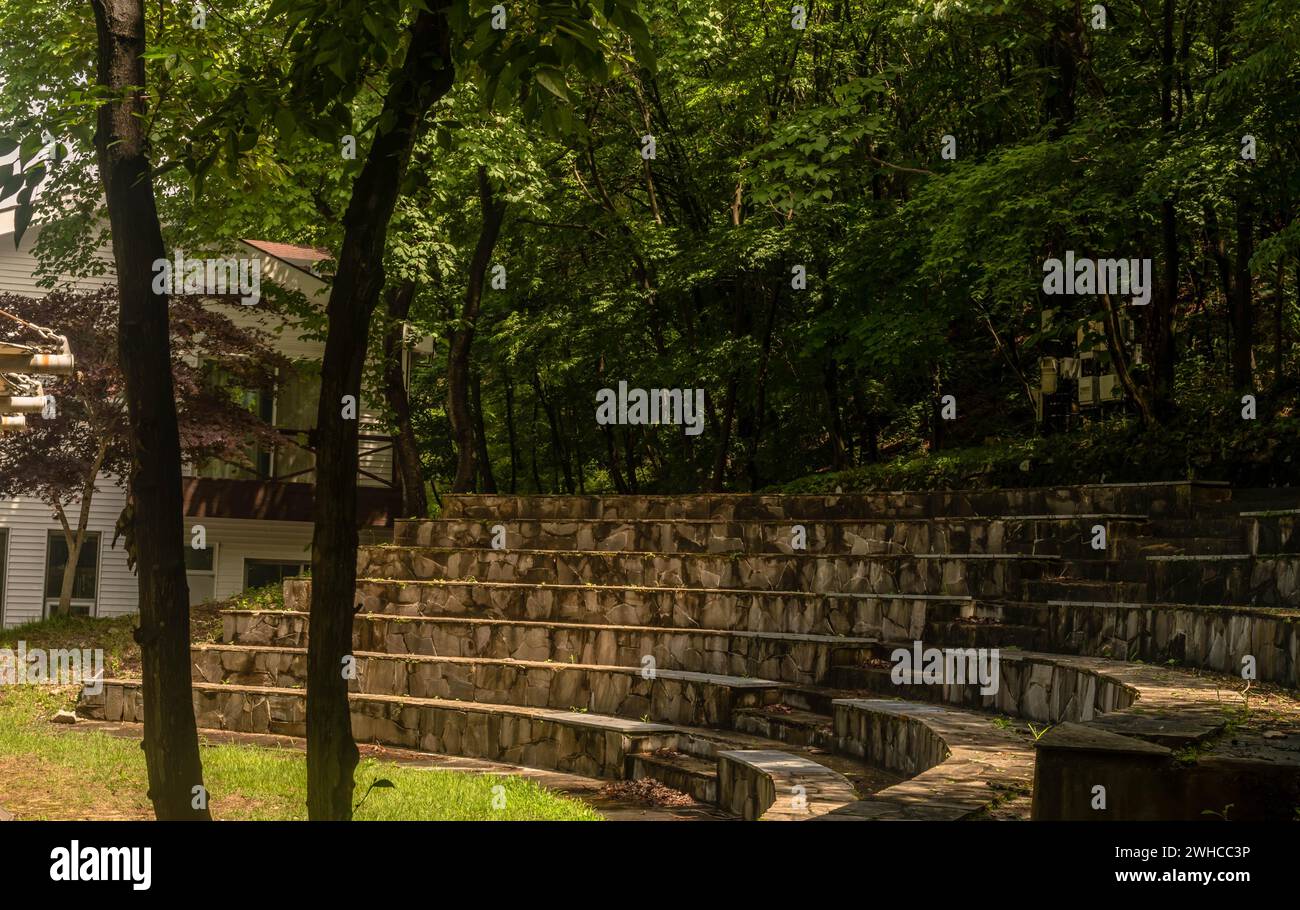 Rock and stone stadium seating under shade trees at recreational forest ...