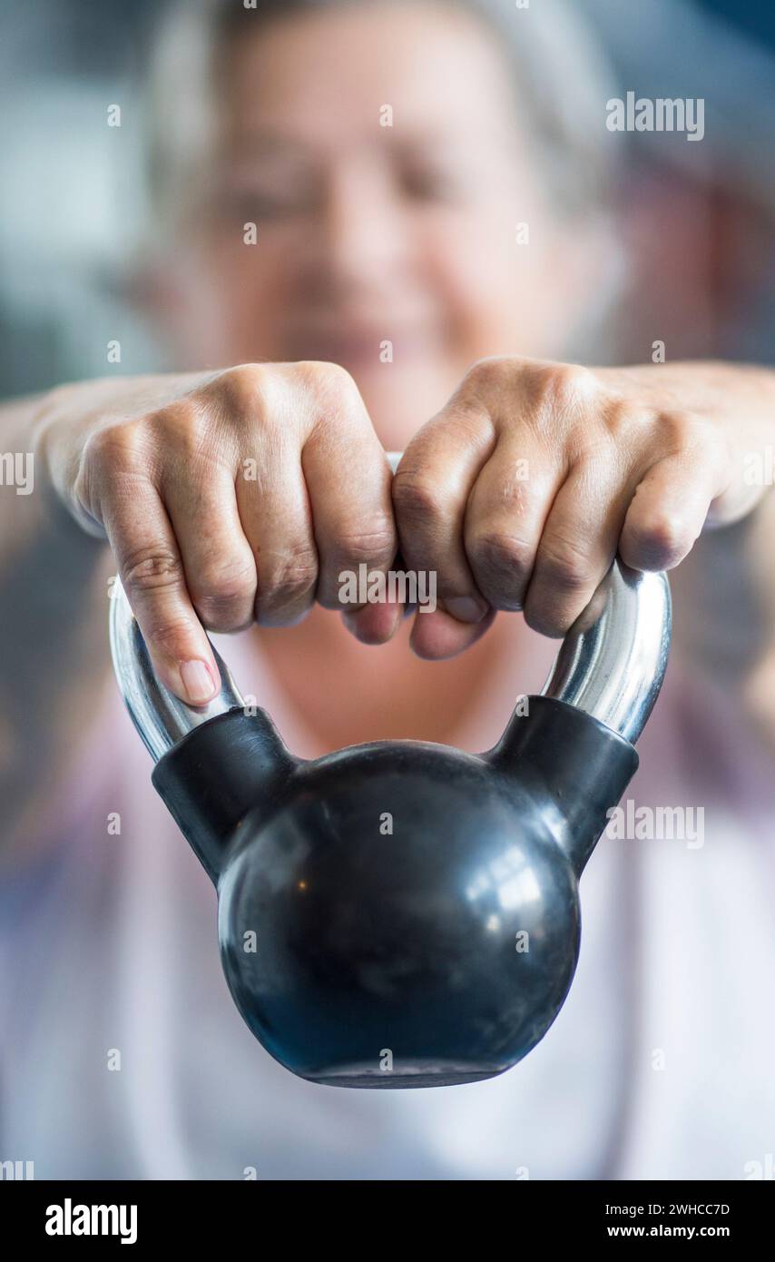 close up of senior holding a weight with his hands in front of the ...
