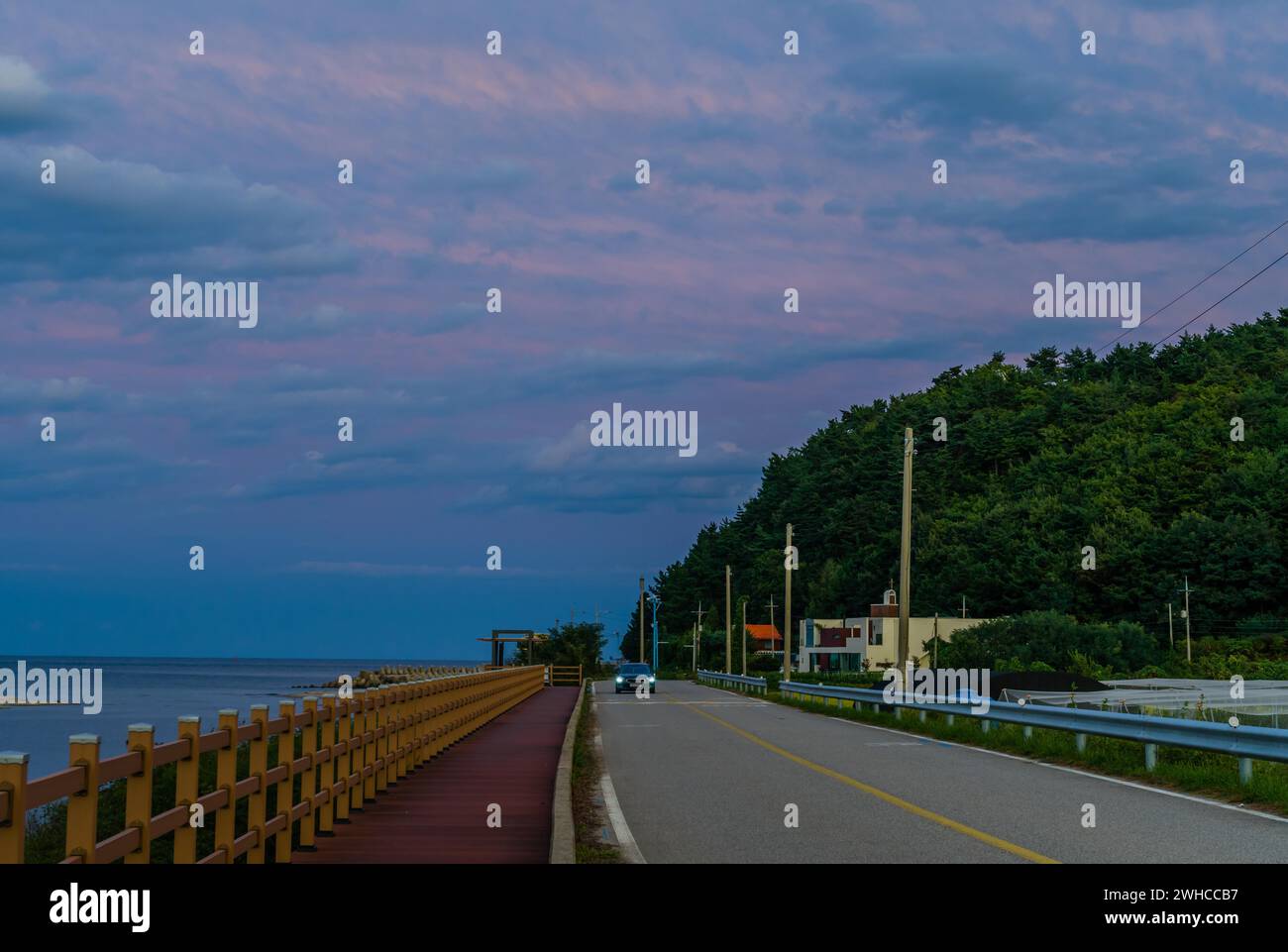Car traveling on two lane country road along oceanside boardwalk under ...