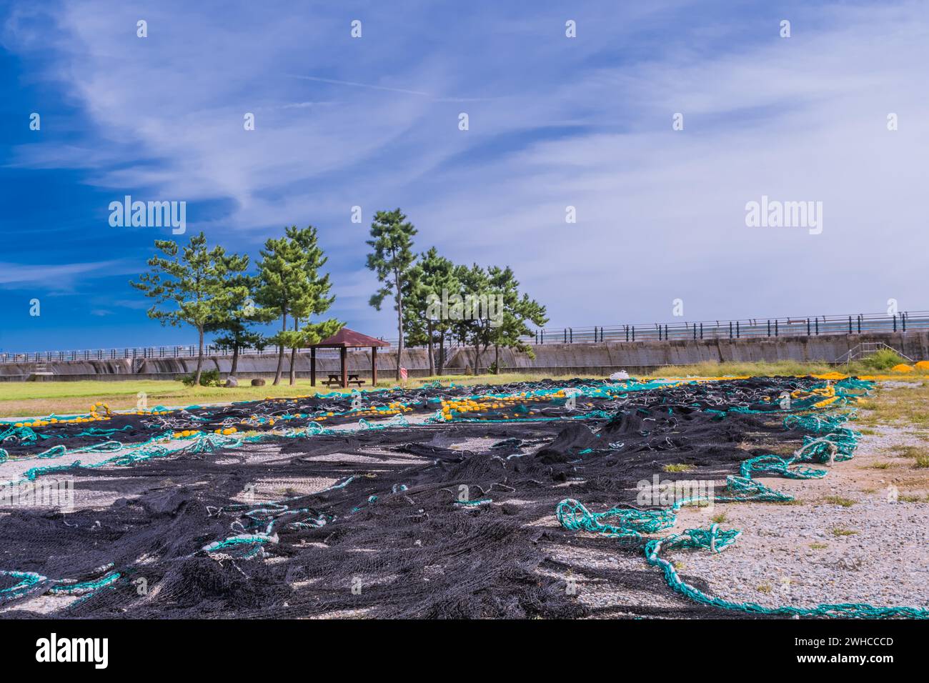 Large fishing nets laid out to dry in gravel lot in front of sea wall ...