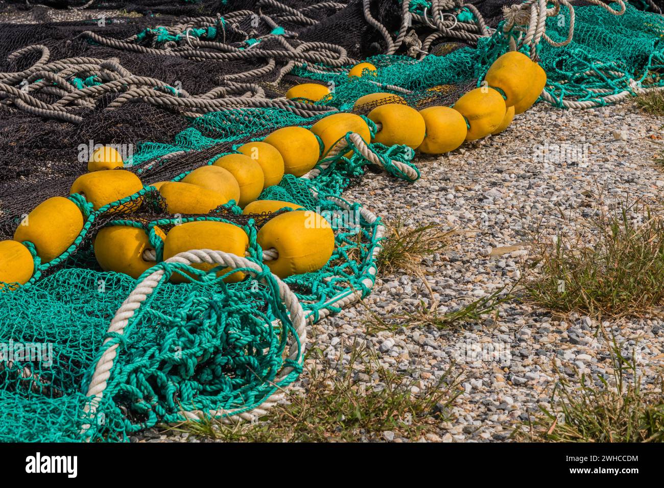 Closeup of large black and green fishing nets with yellow floats laid ...