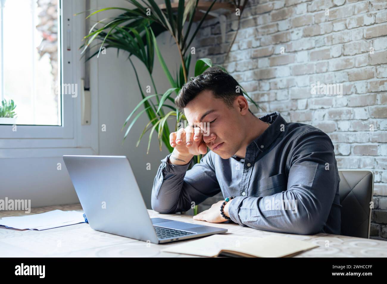 Tired young man feel pain eyestrain holding glasses rubbing dry ...
