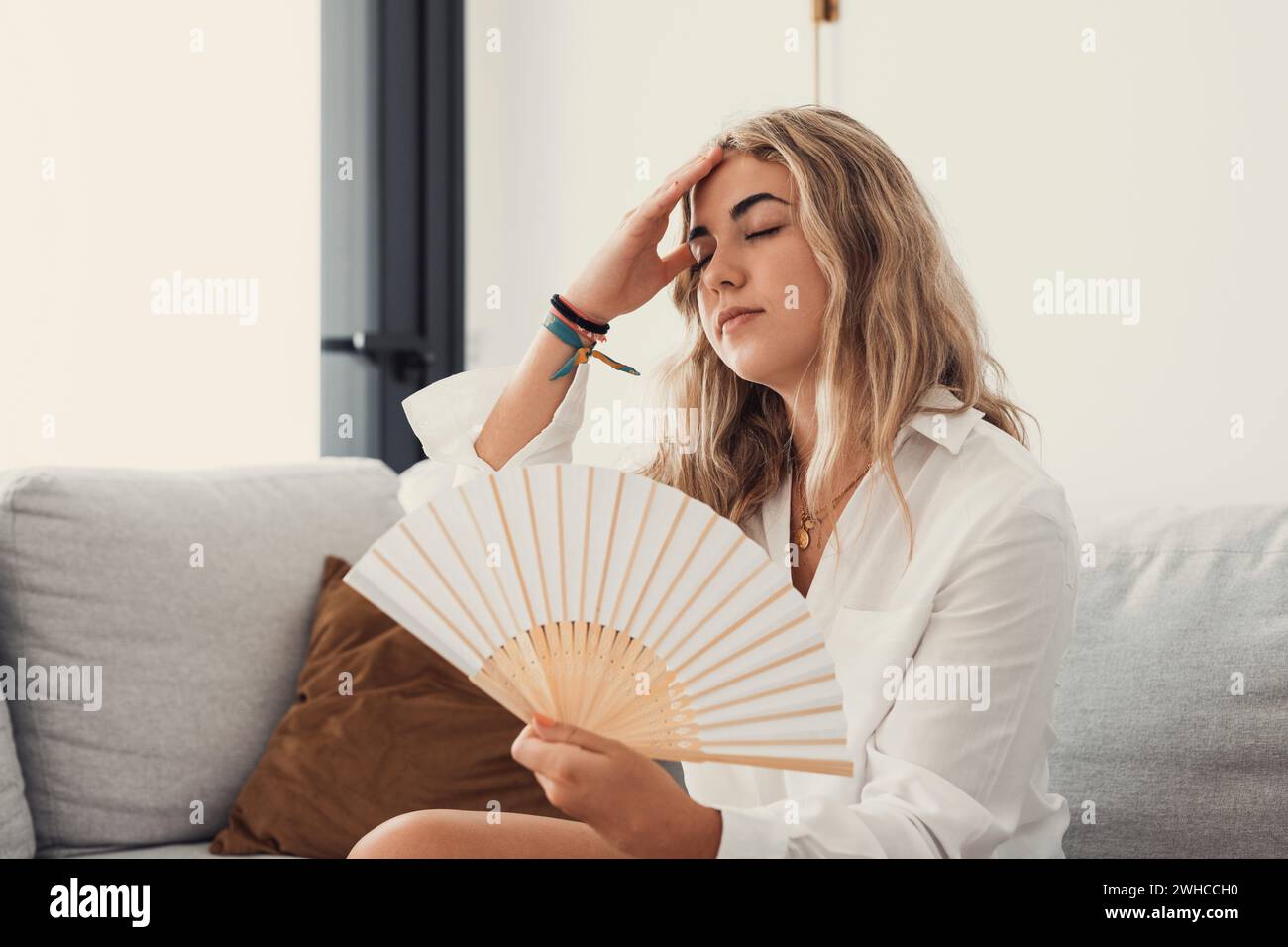 Overheated female sitting on couch in living room at hot summer weather ...