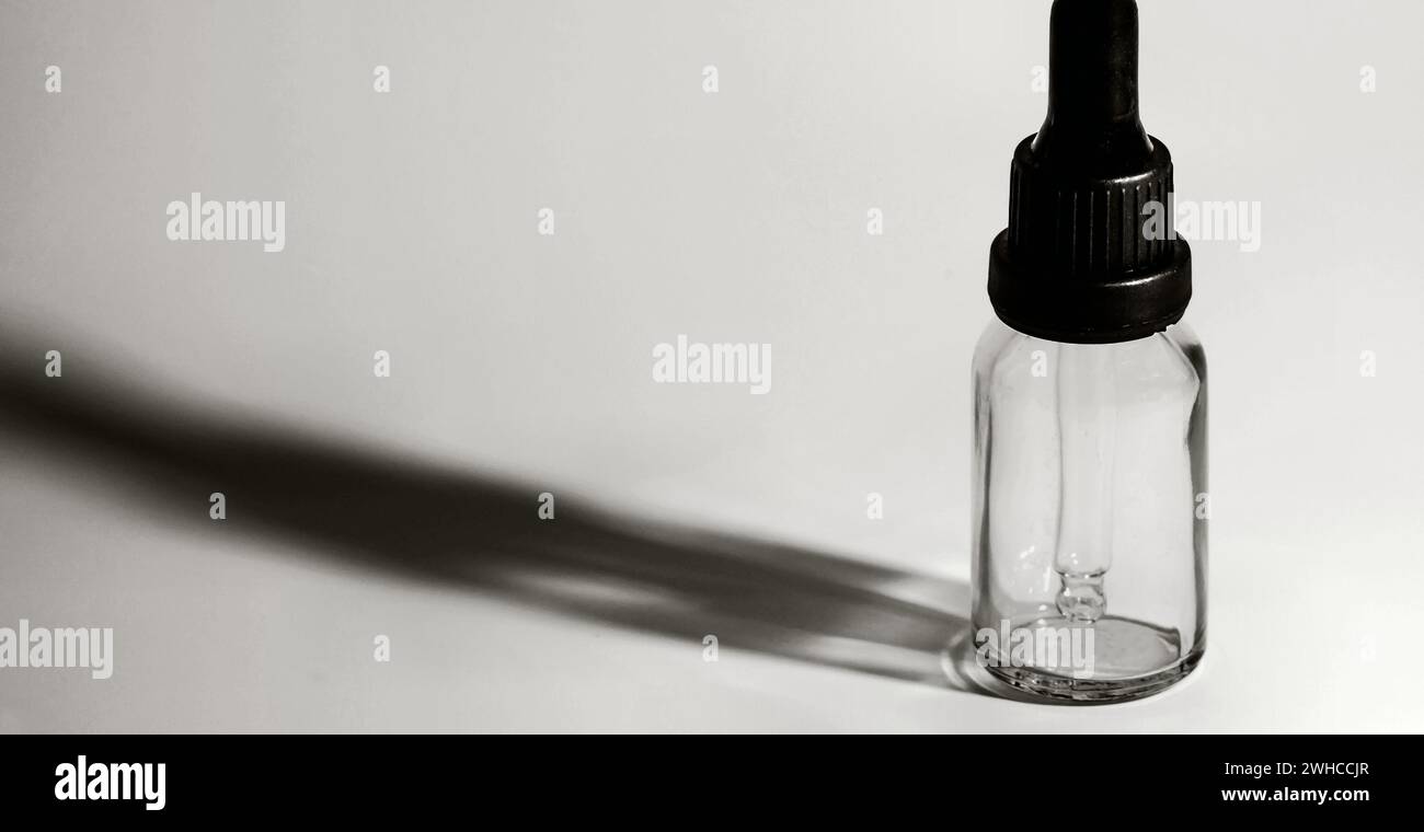 Closeup of single eye dropper bottle with strong dark shadow on white ...