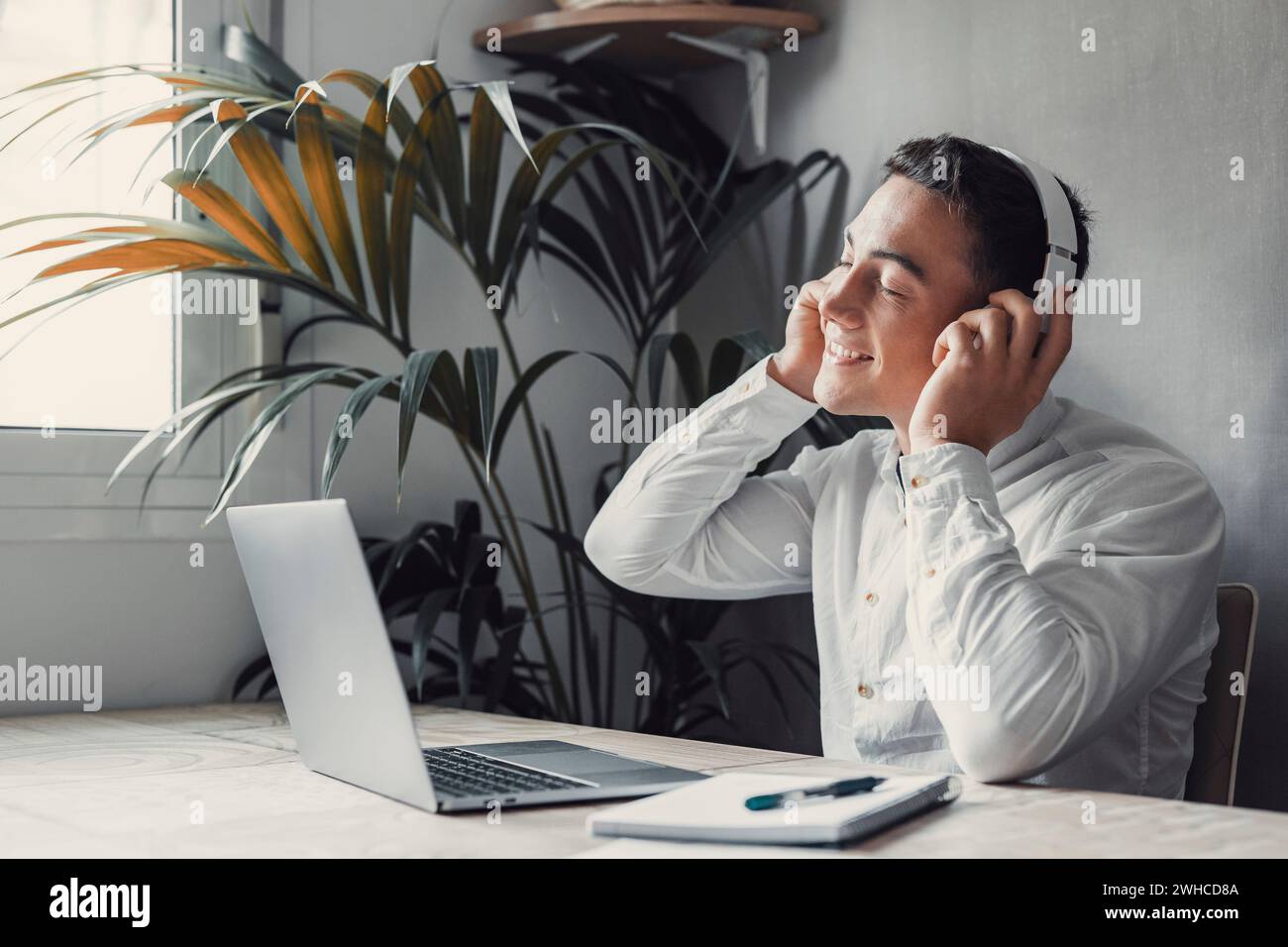 Happy businessman wearing headphones singing song at workplace, funny ...