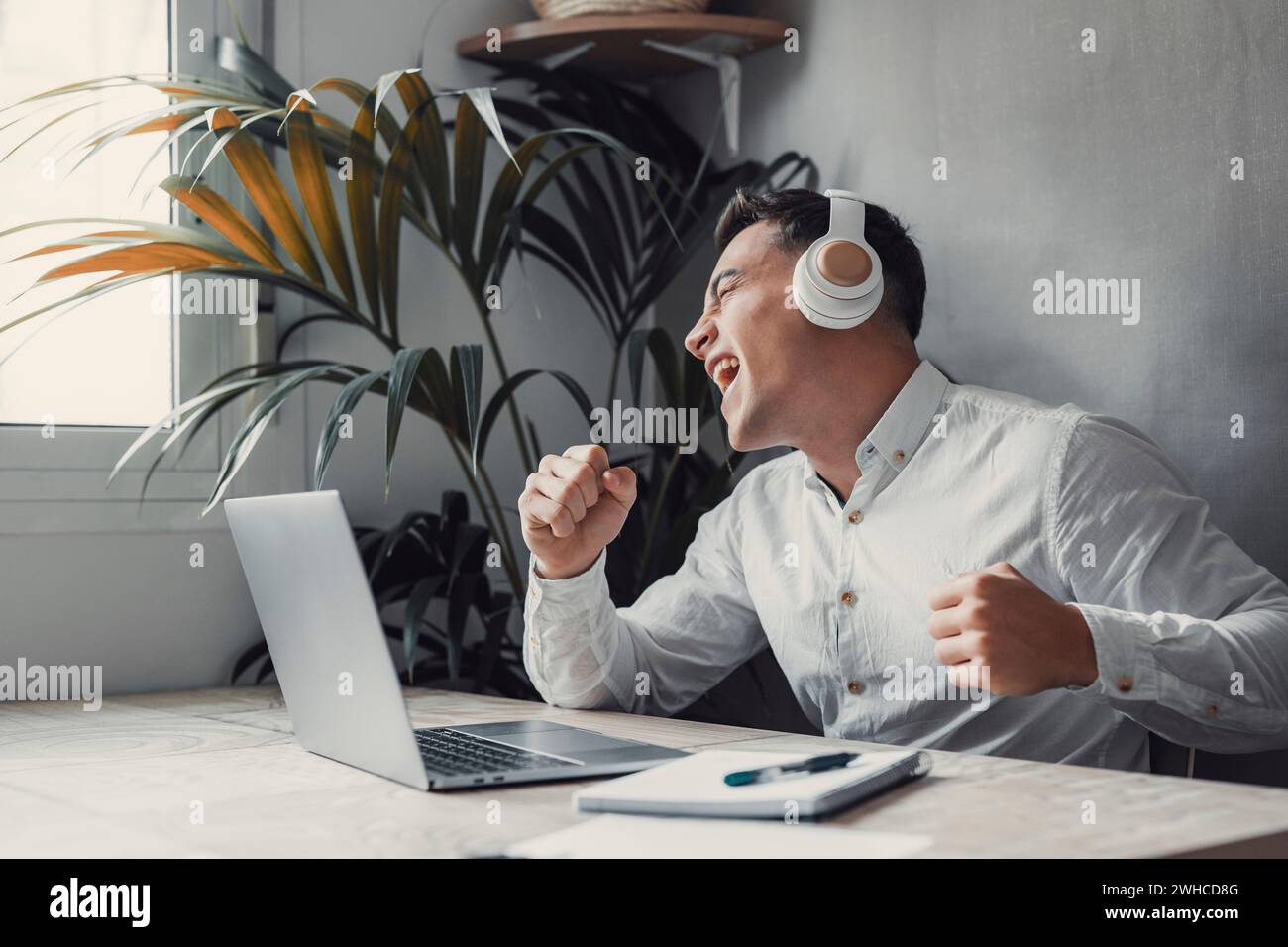 Happy businessman wearing headphones singing song at workplace, funny ...