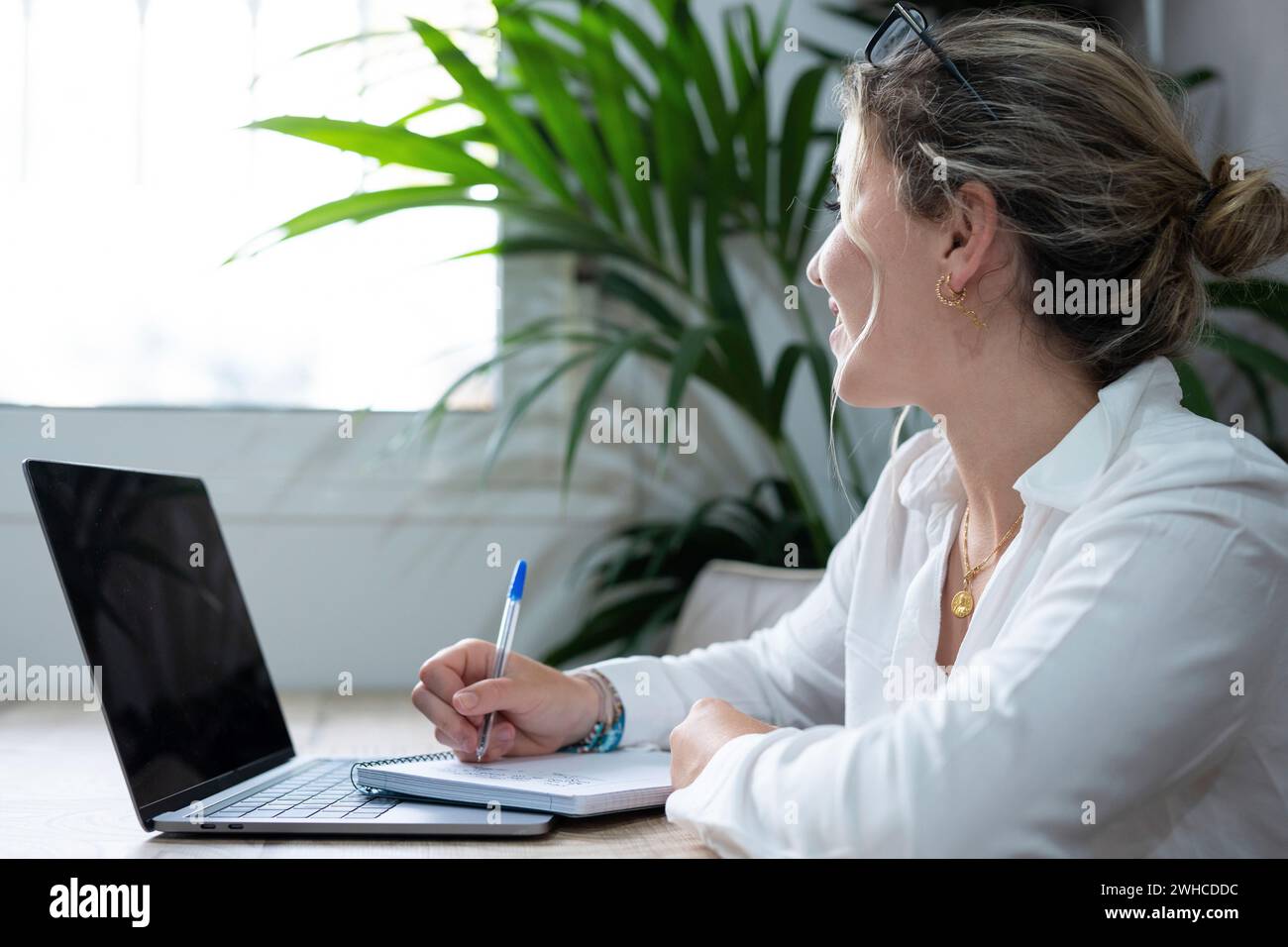 Millennial smiling caucasian girl sit at desk in living room study on ...