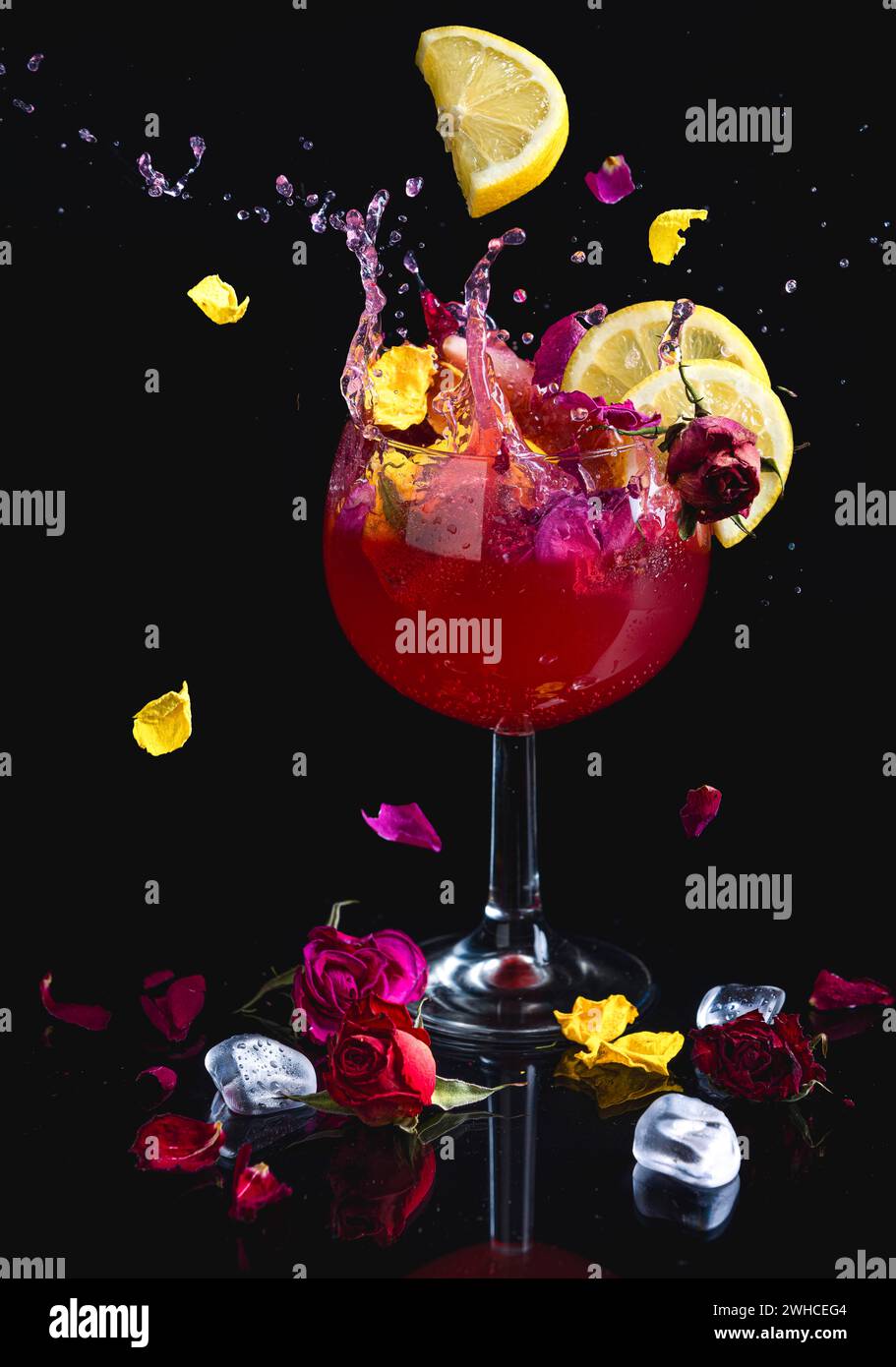 A colourful splashing cocktail with lemon slices, surrounded by flowers ...