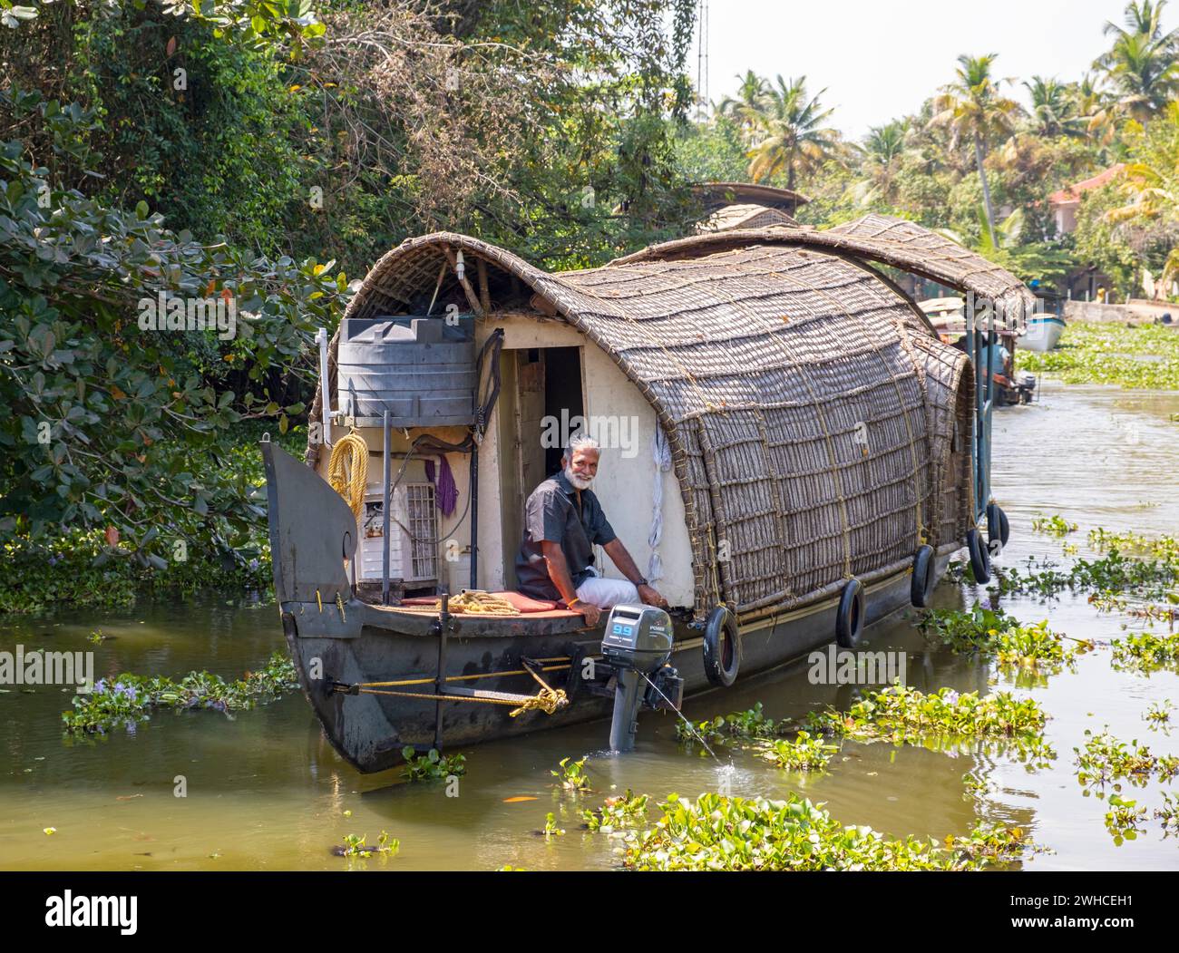 A traditional houseboat cruises along the channels near Kumarakom ...