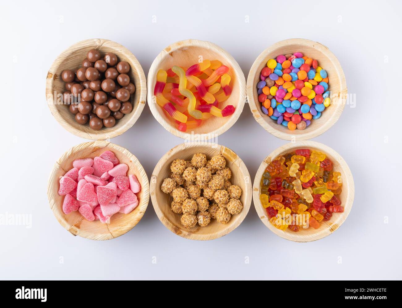 Symmetrical arrangement of different sweets in round bowls on a white ...