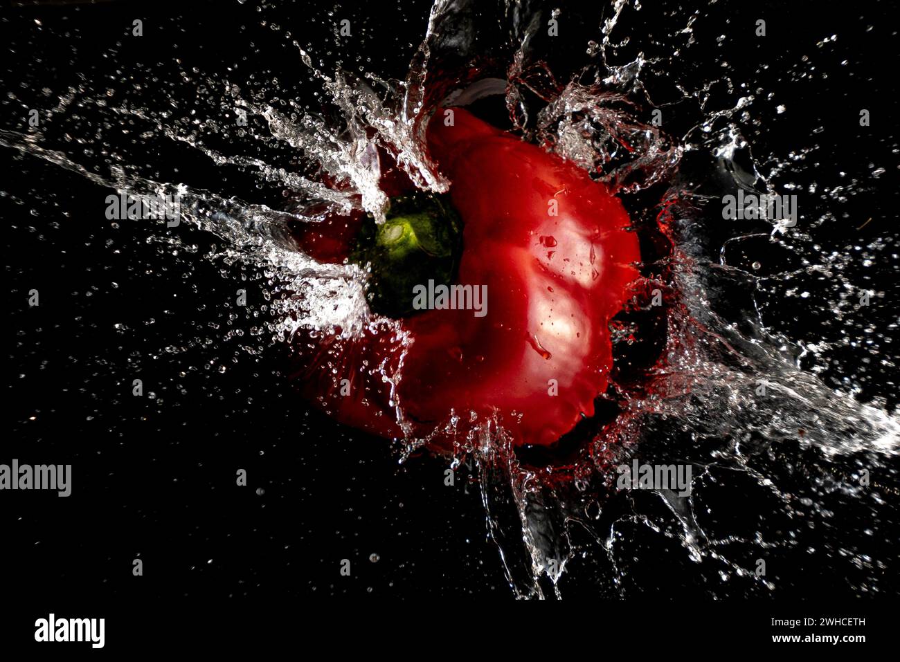 Red pepper in the centre of a dynamic water splash in the dark Stock ...