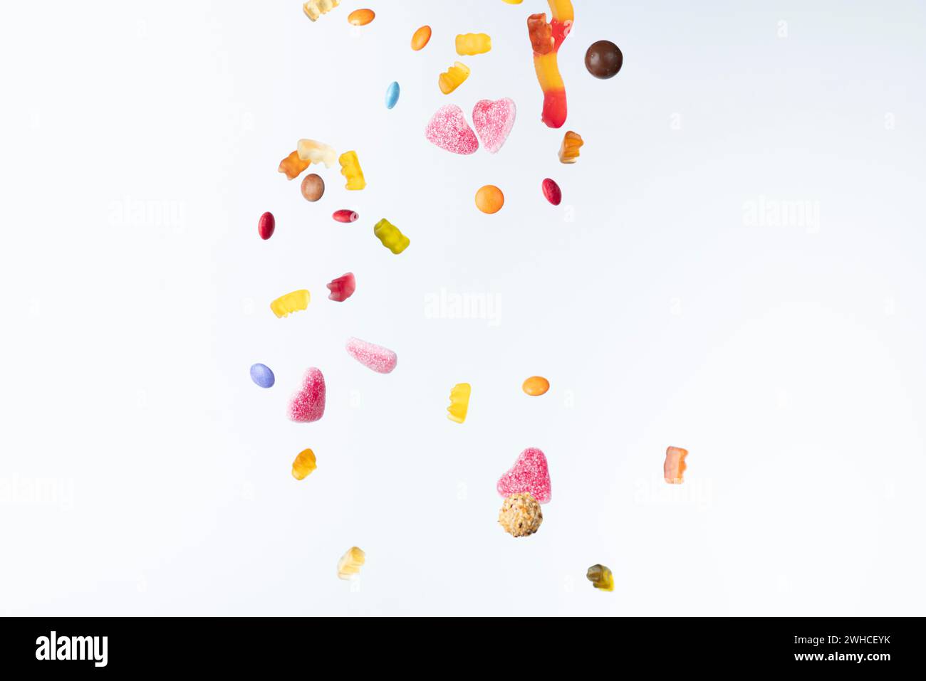 Colourful sweets fall against a white background Stock Photo - Alamy
