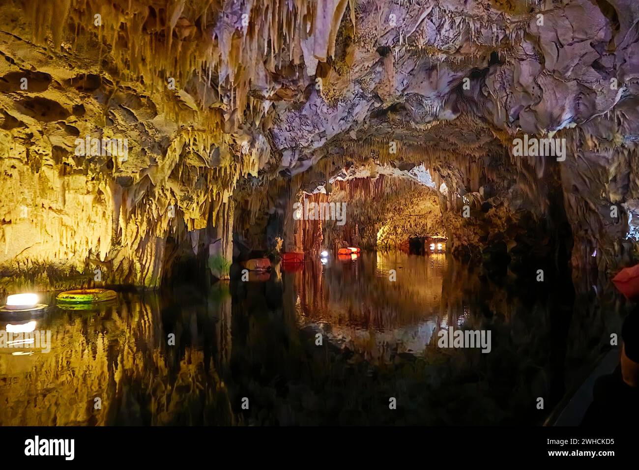Cave interior with water, stalactites on the ceiling and boats ...