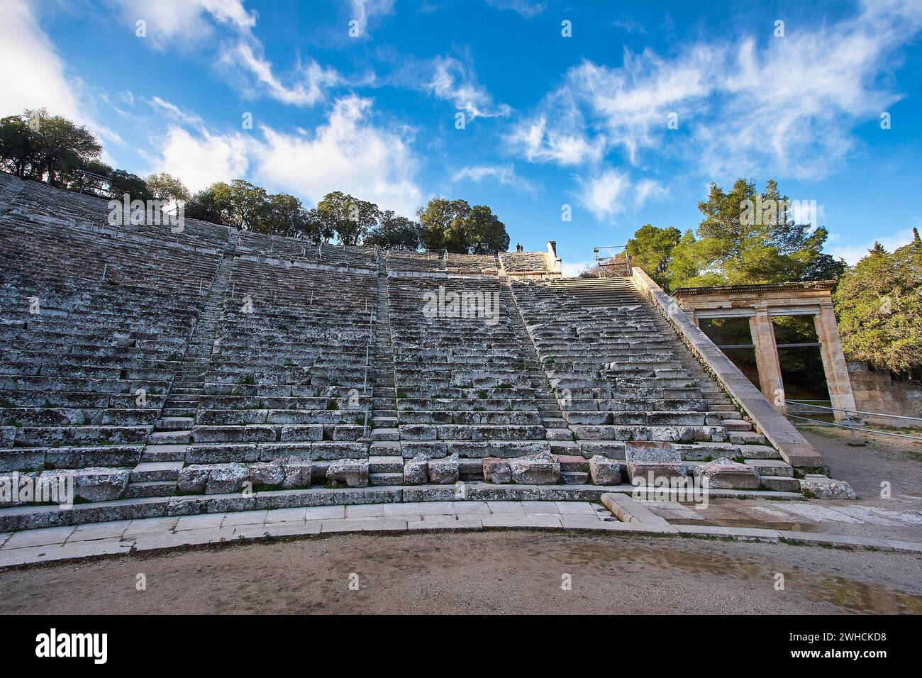 The ruins of an ancient theatre with empty stone steps and a clear blue ...