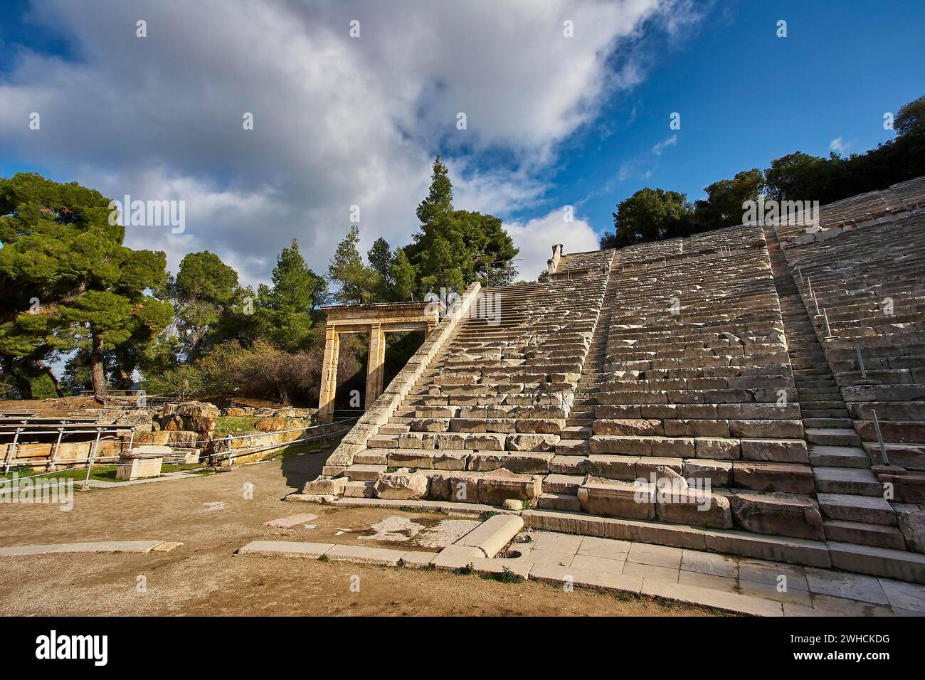 Partially restored amphitheatre under a blue sky next to green ...