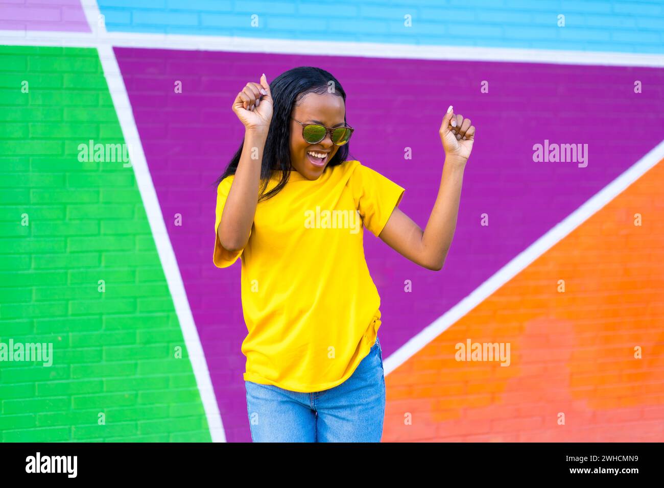 Frontal portrait of a young and happy african woman smiling and dancing ...