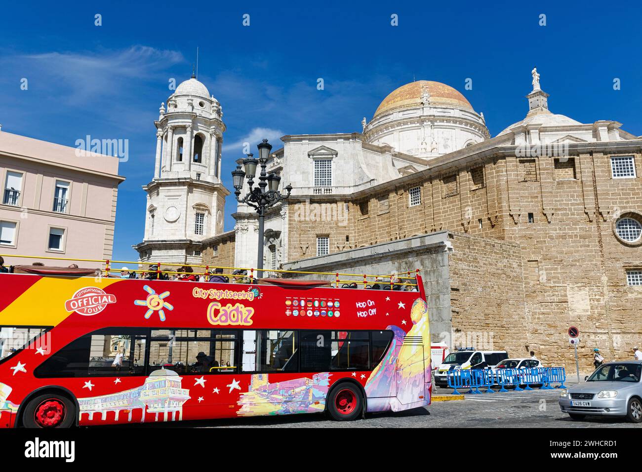 Red double-decker bus with tourists in front of the cathedral of Cadiz ...