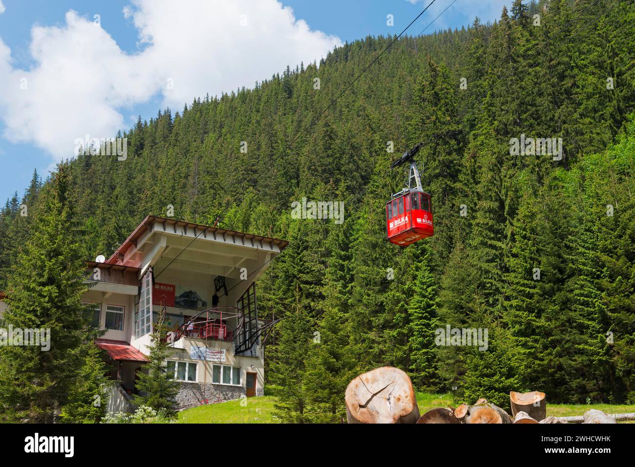 Cable car station in a green mountain landscape with a red cable car ...