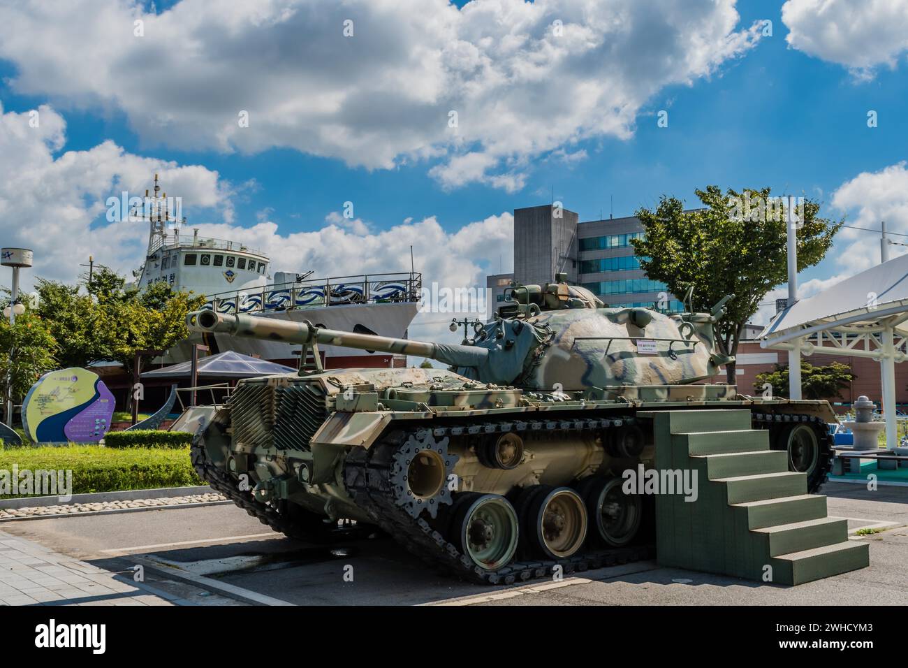 Side view of M48 tank on display at seaside park under blue cloudy sky ...