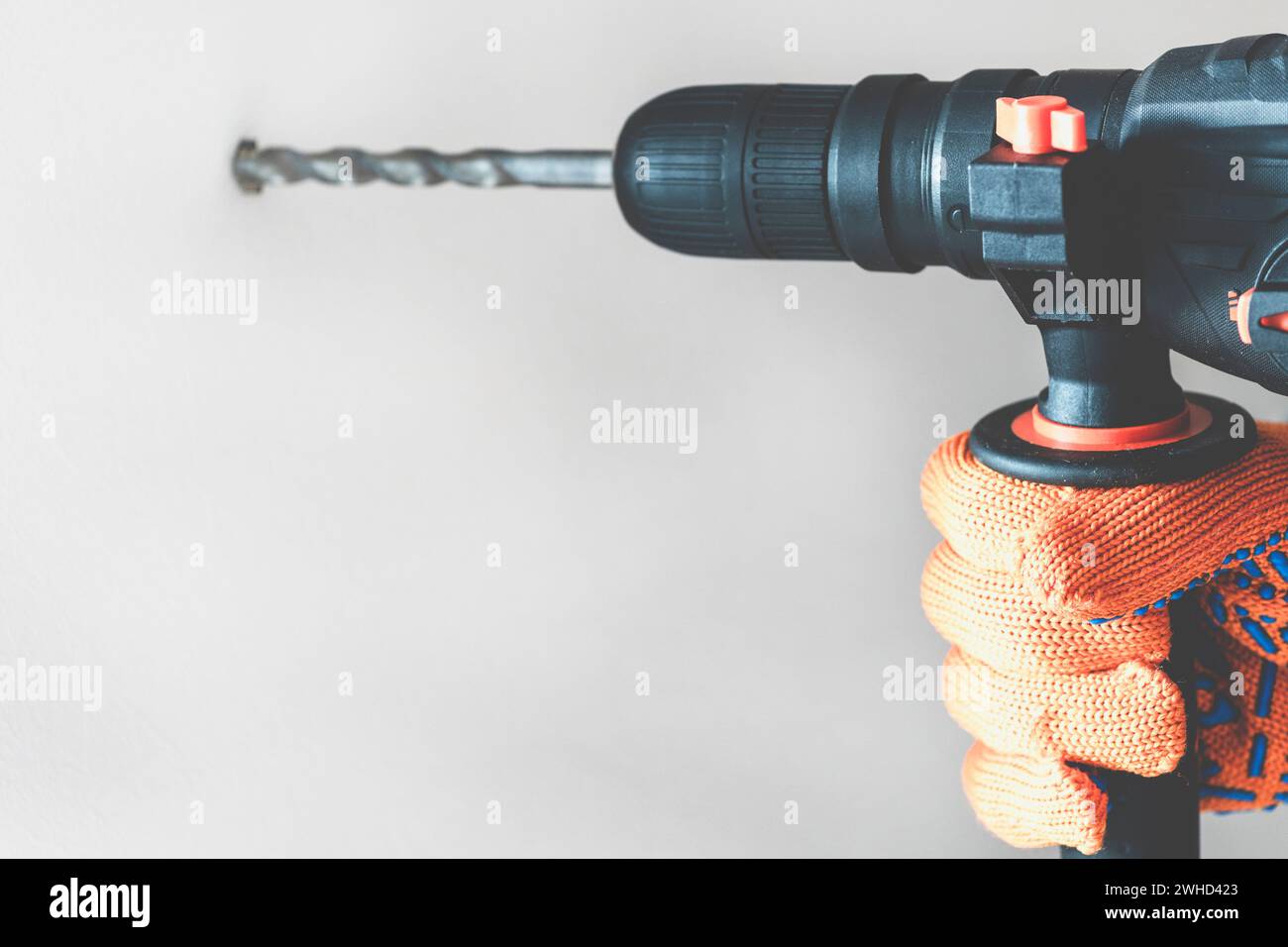 workman hand with a rotary hammer. Hands in protective gloves with ...