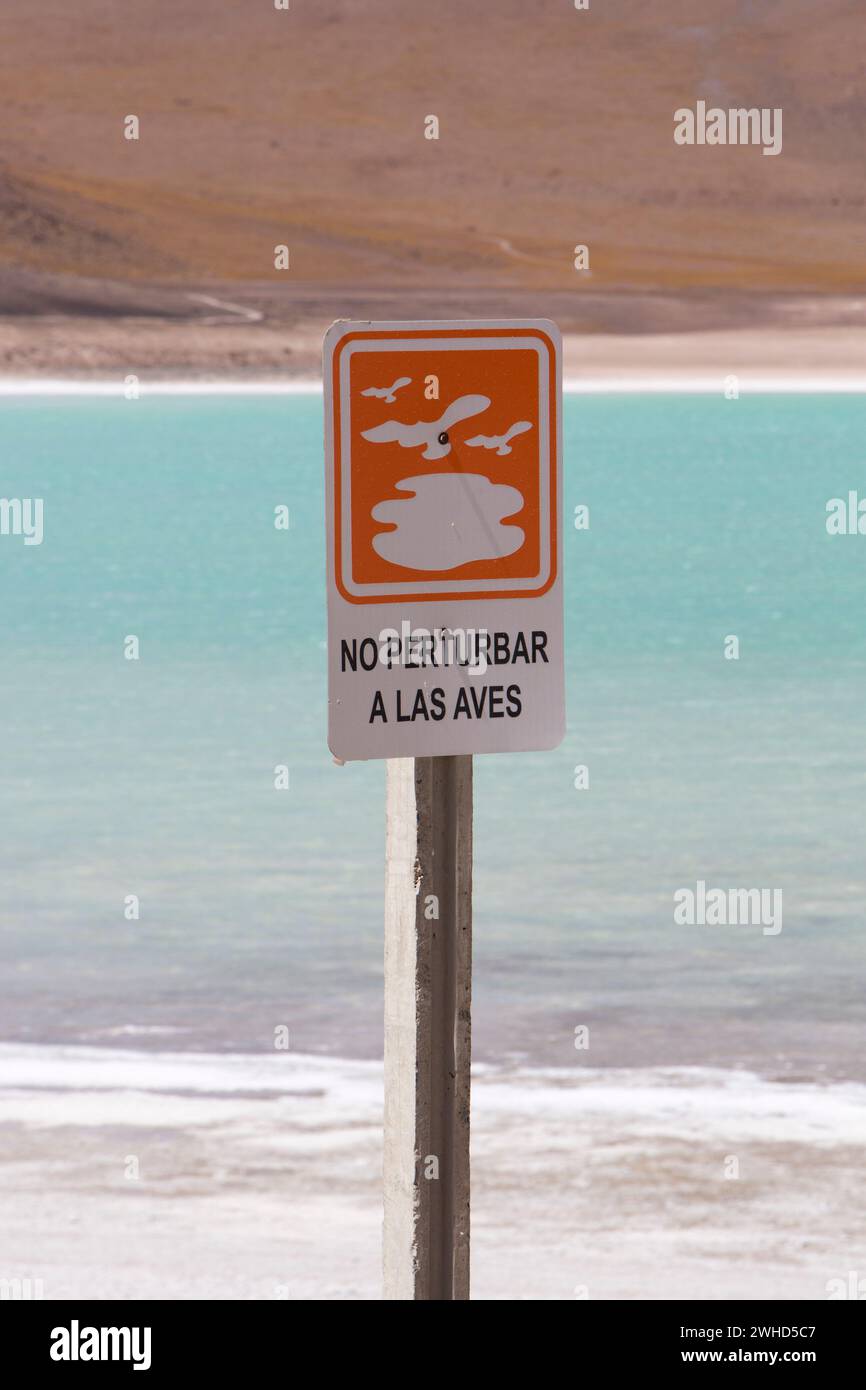 Warning sign with the volcanic lake at the Eduardo Avaroa National Park ...