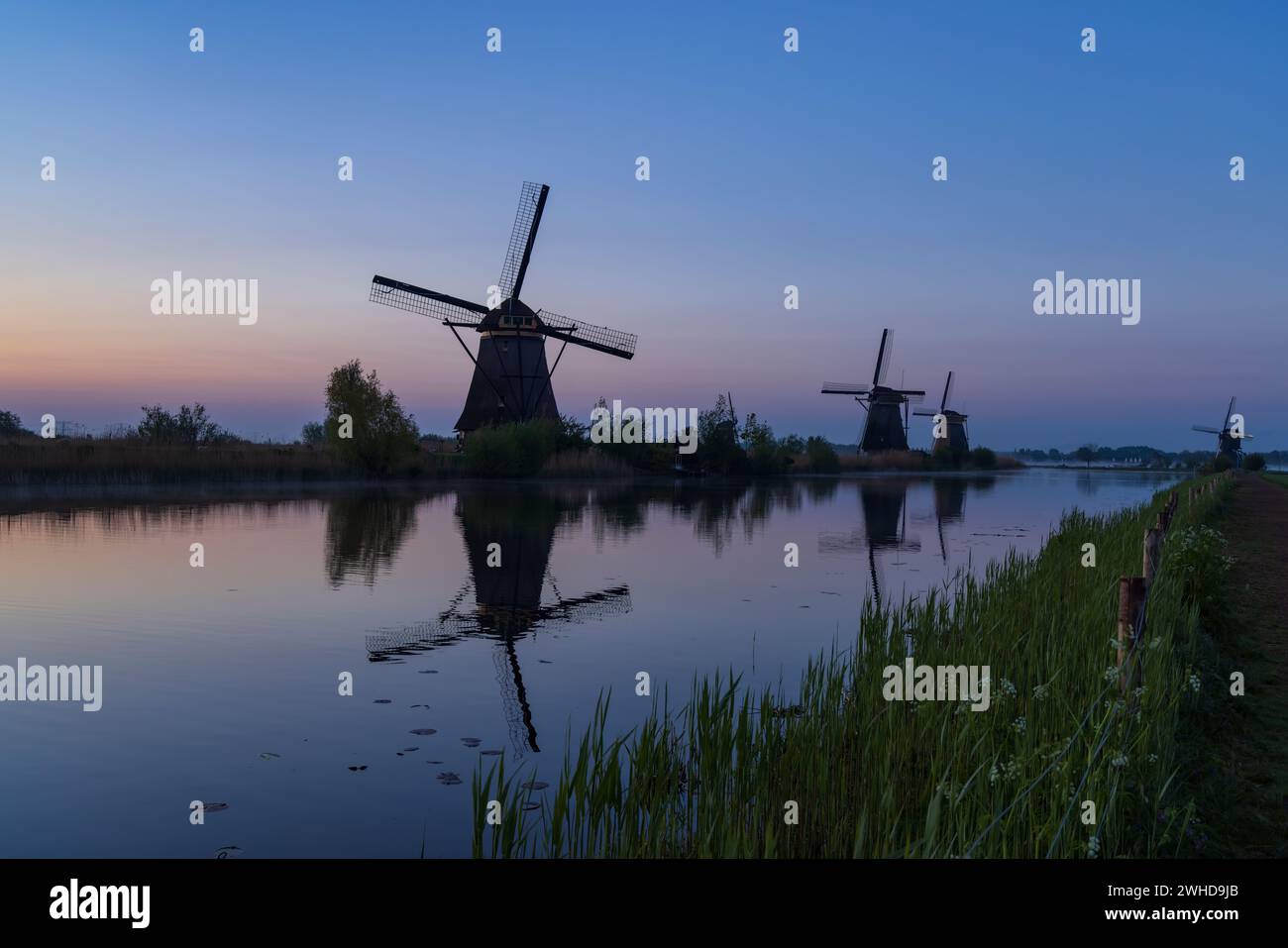 Traditional Dutch windmills with a colourful sky just before sunrise in ...