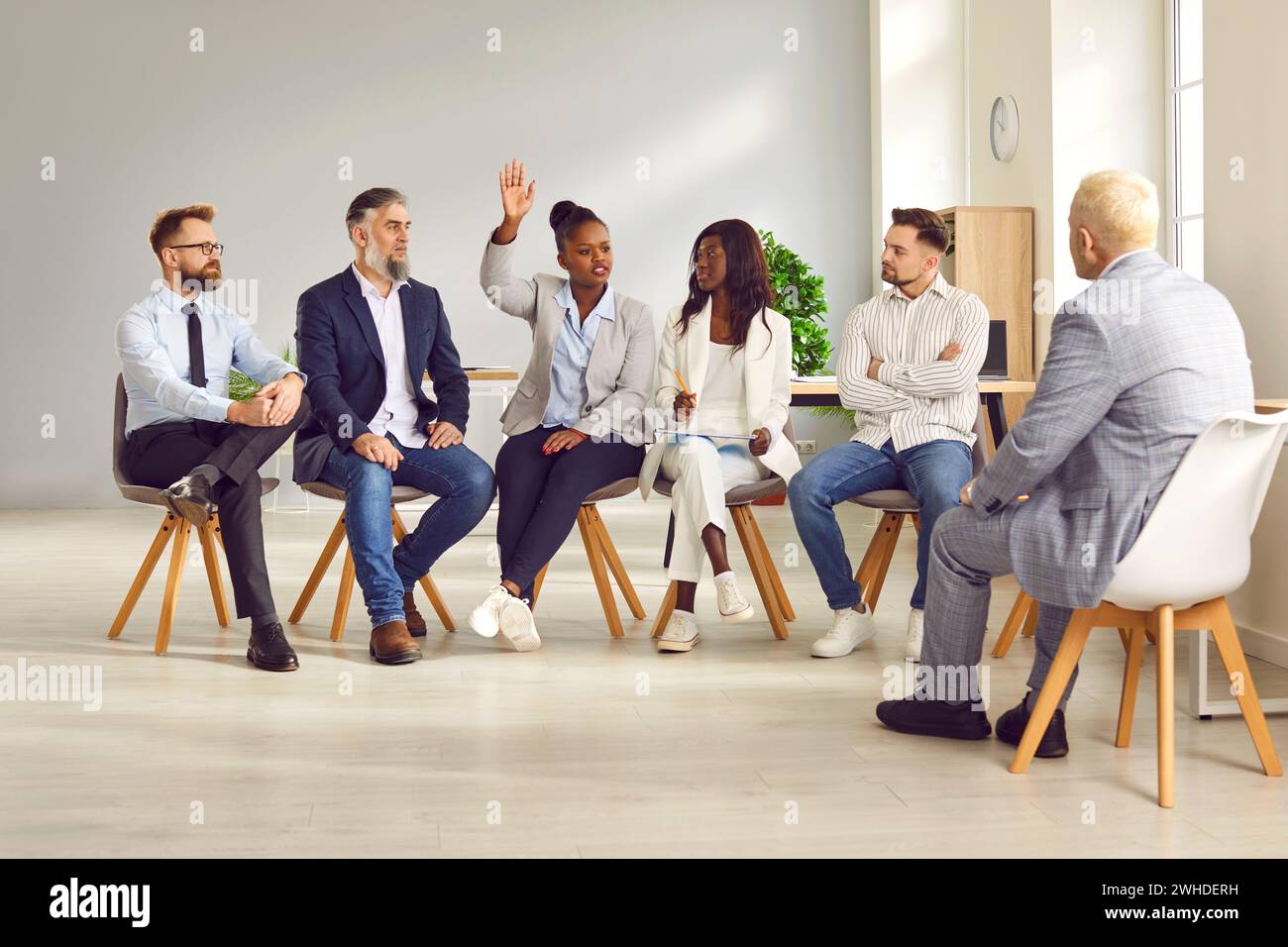 Group of company employees or a team of staff sitting on chairs in a ...