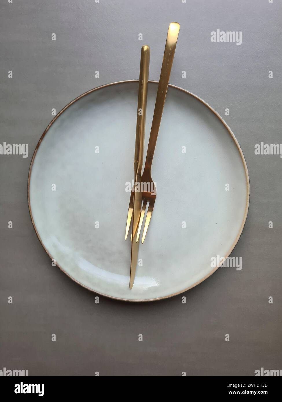 Natural-colored ceramic plate with brown rim and gold-colored knife ...
