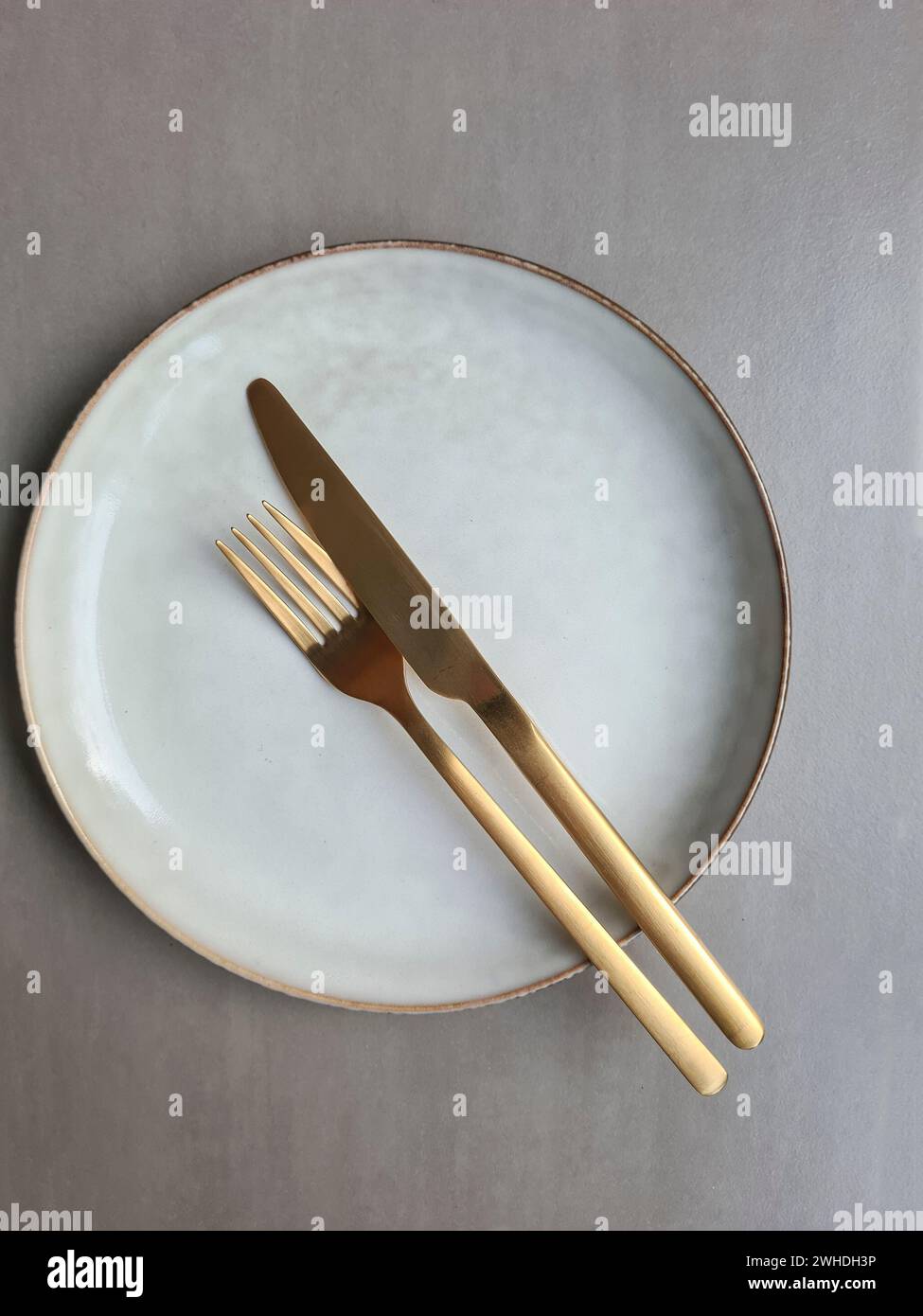 Natural-colored ceramic plate with brown rim and gold-colored knife ...