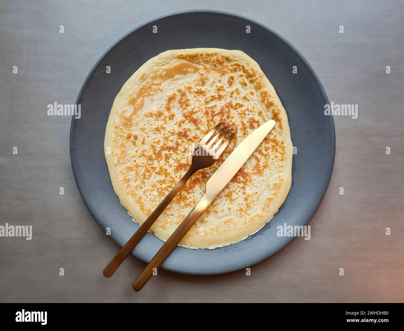 Pancakes on a gray plate with golden cutlery, egg dish with knife and ...